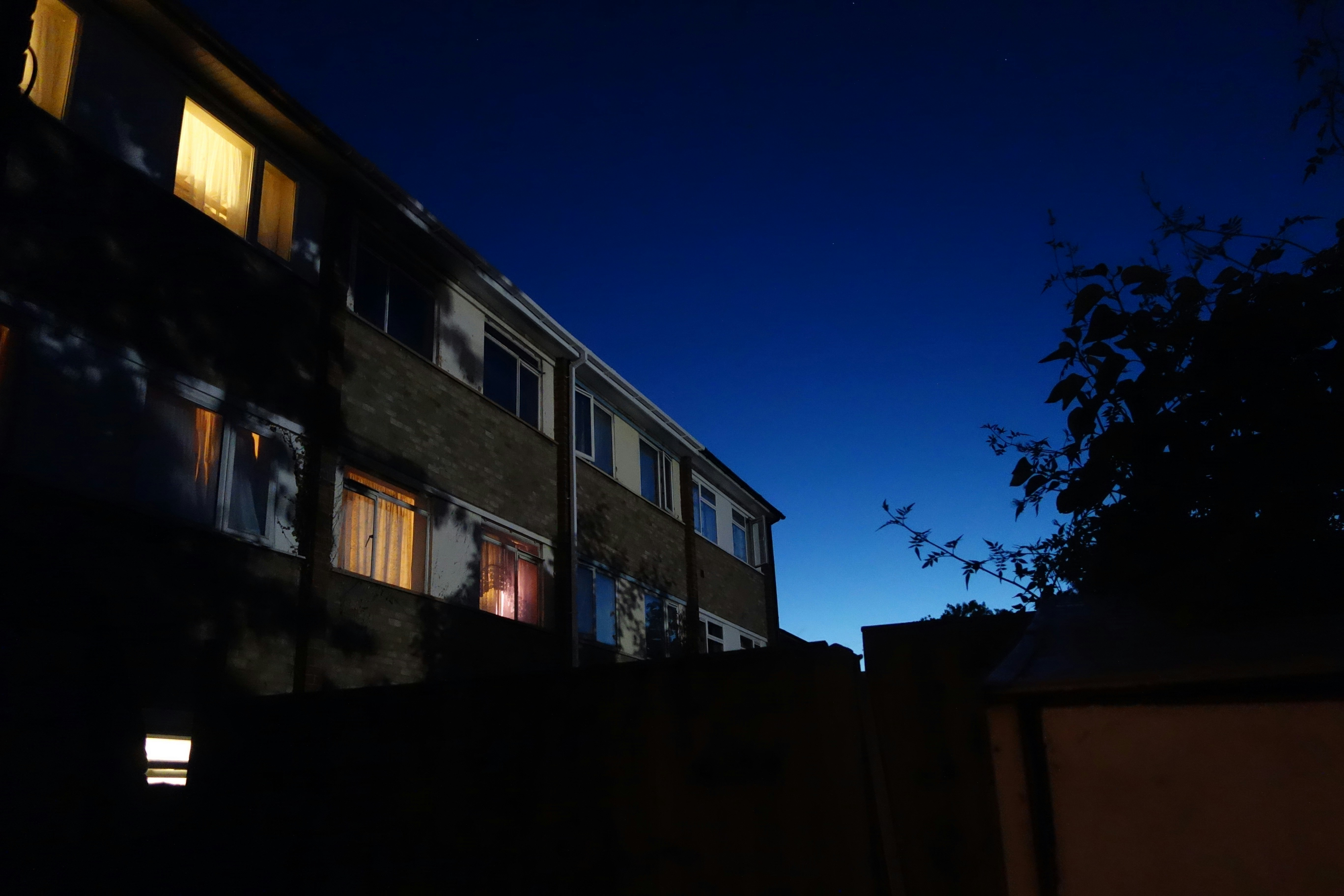 Silhouetted houses under a deep blue twilight sky, with warm lights glowing from the windows, creating a serene and inviting atmosphere.
