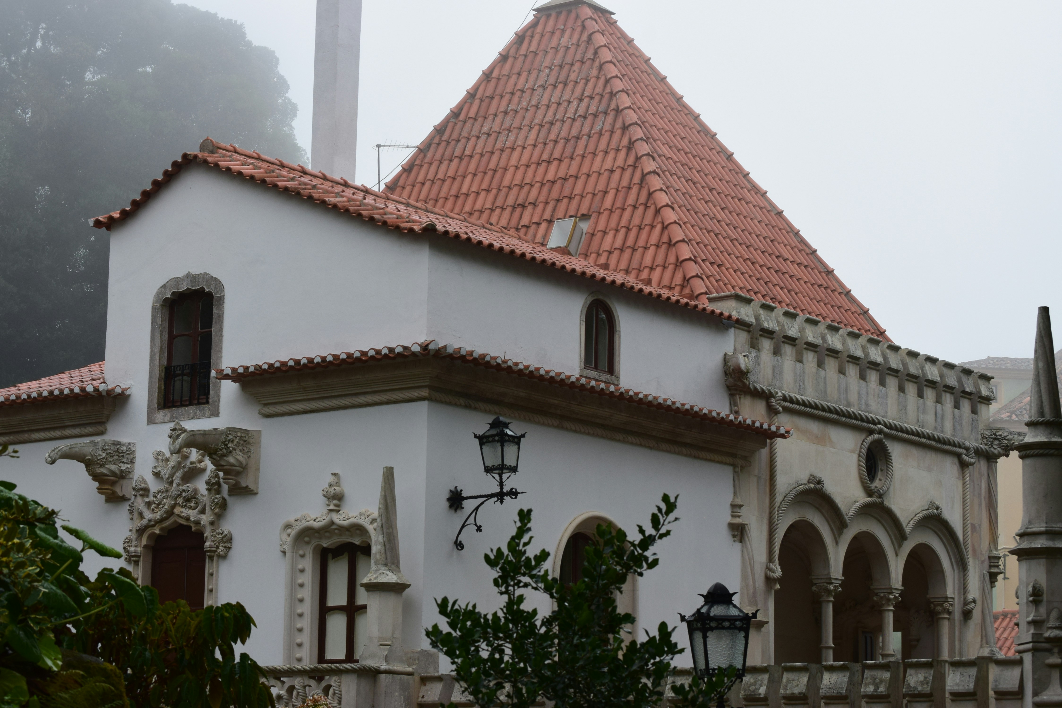 Arcaded White Villa Emerges Through Morning Fog Under a Terracotta Roof