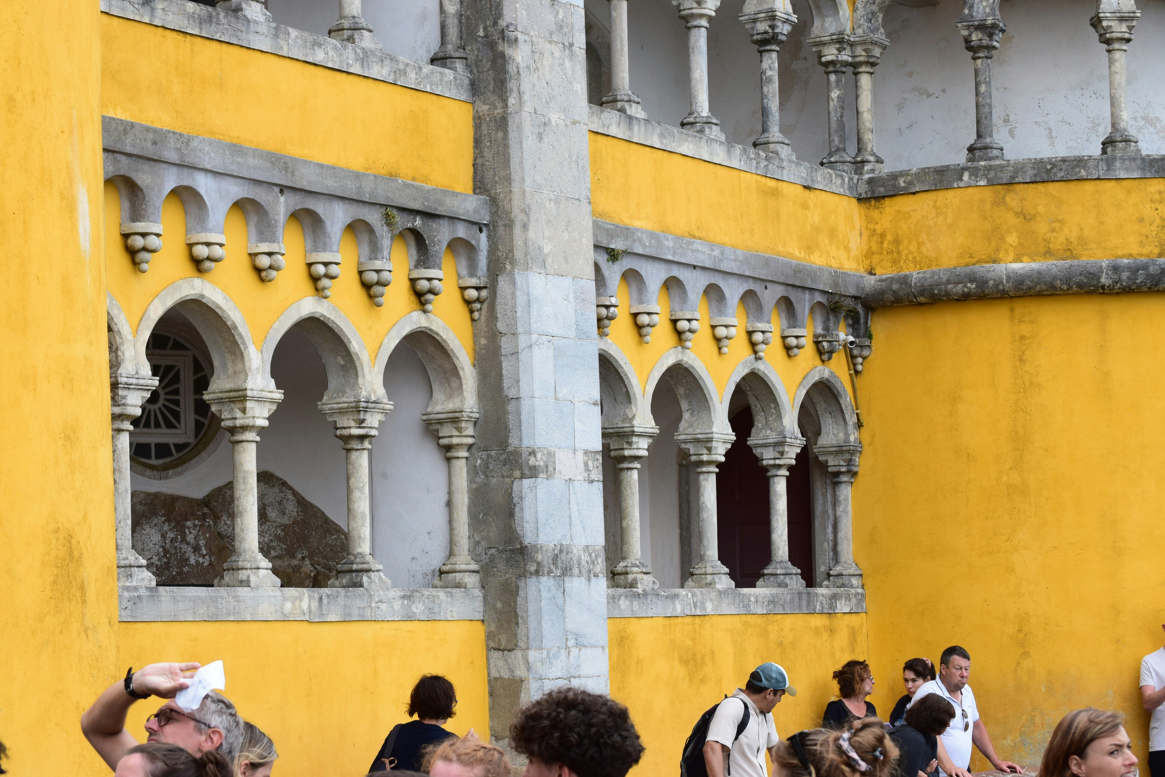 A group of people walking by a building with arches photo – Free Person ...