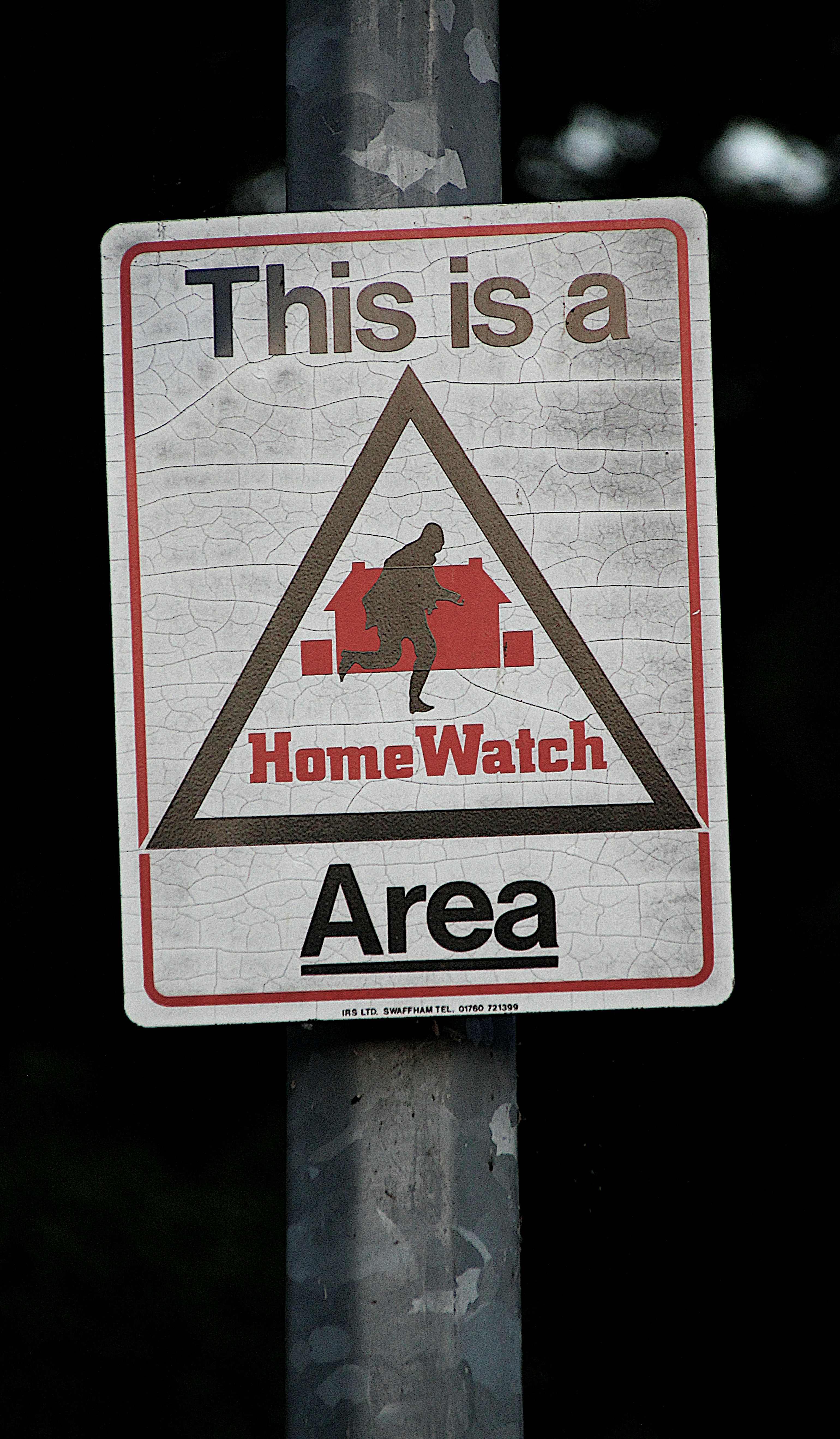 HomeWatch Area Sign: A Weathered Warning on a Metal Post