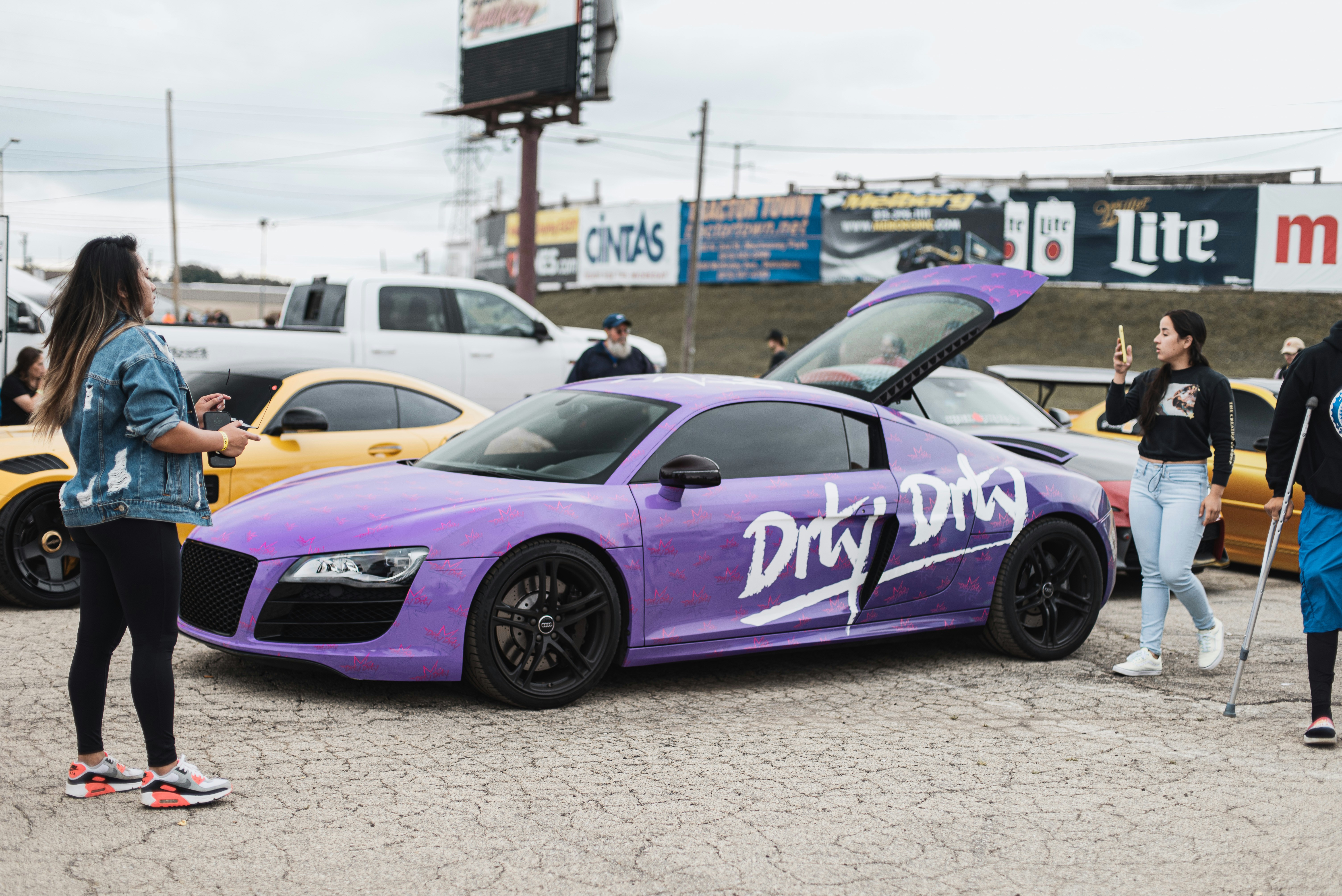 A purple sports car with a spoiler parked on a street with people photo ...