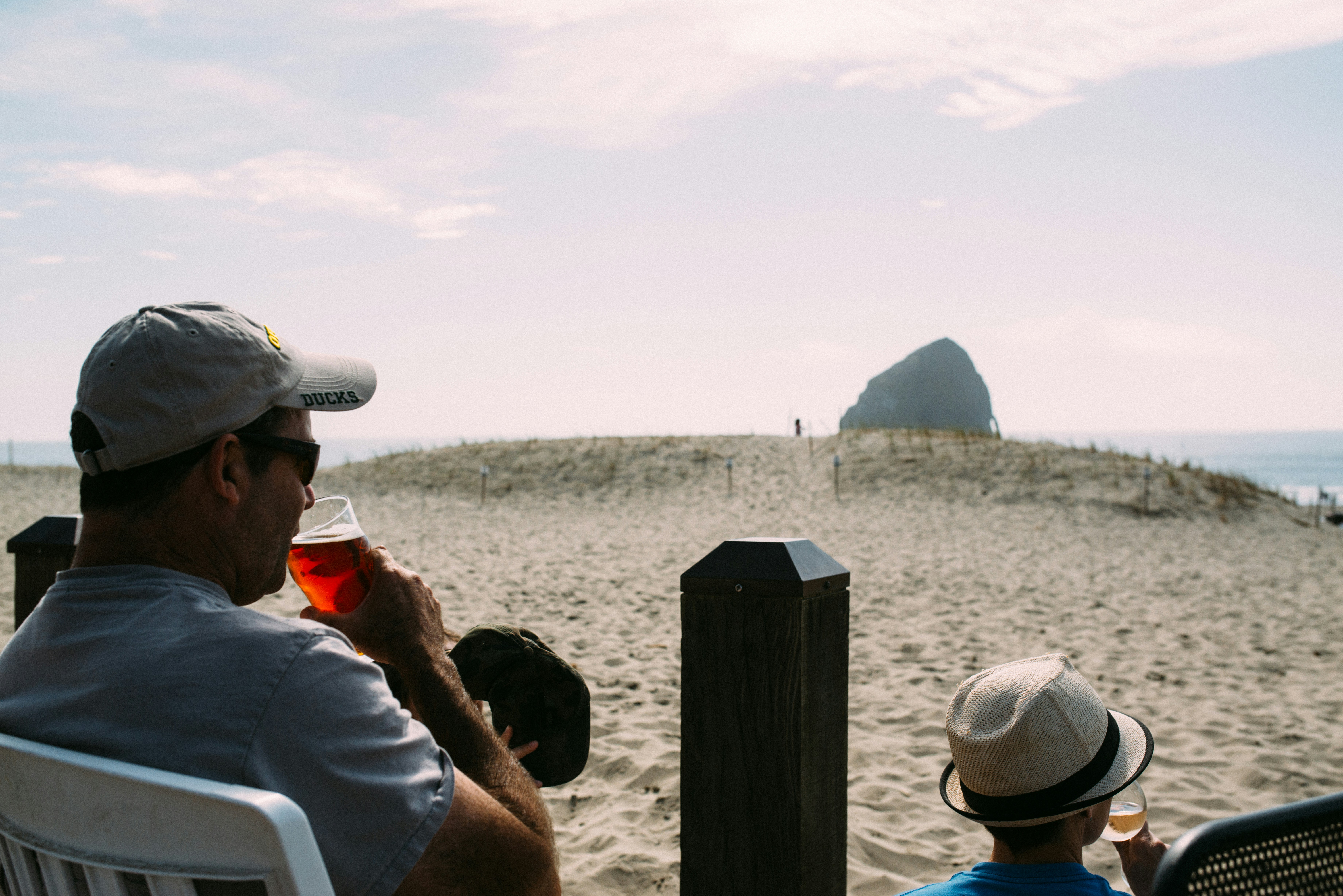 Beachside Pause: People Resting as a Sea Stack Emerges at Dusk