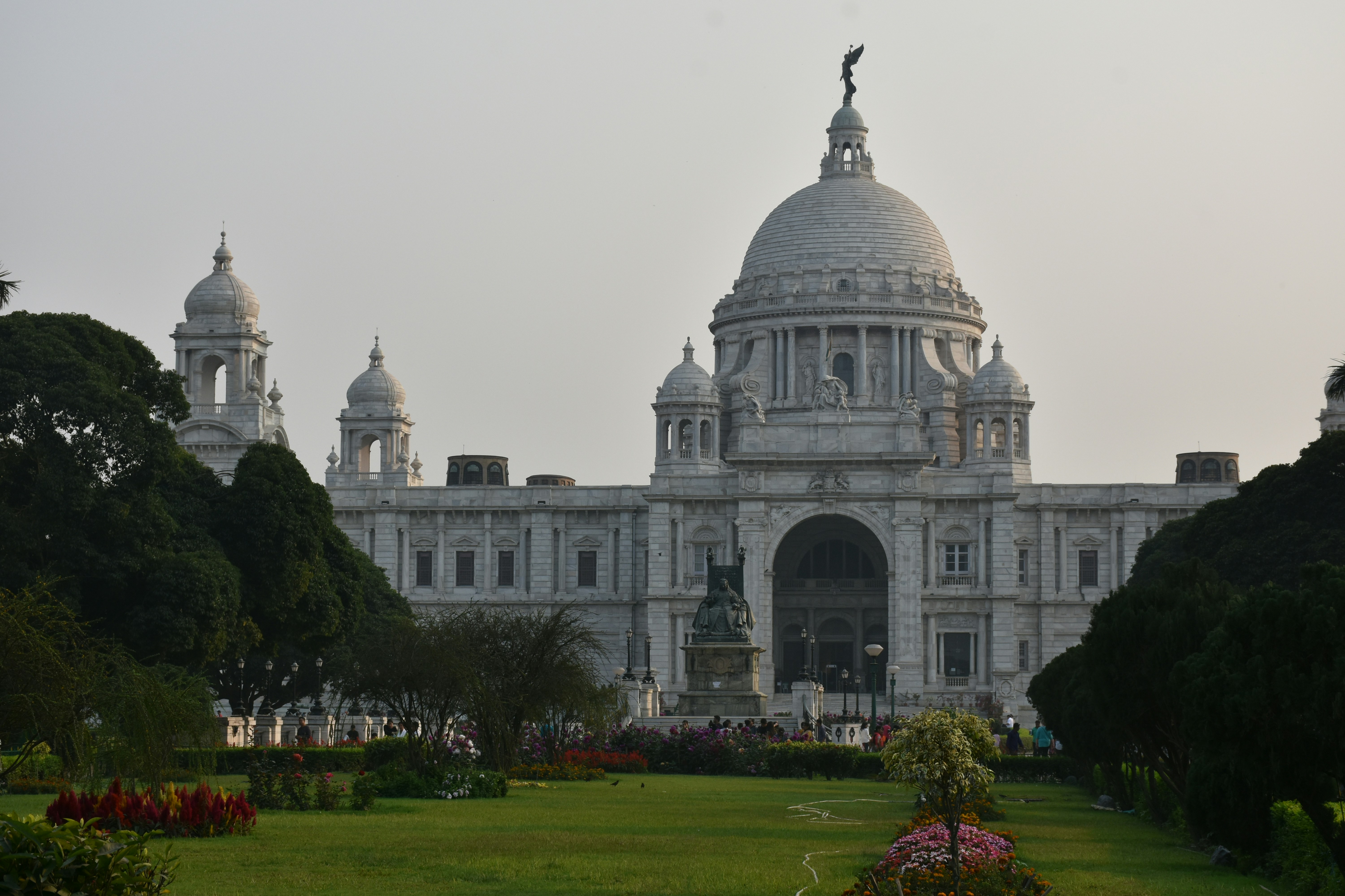 Victorian-era architecture of the Victoria Memorial surrounded by lush gardens and vibrant flower beds.