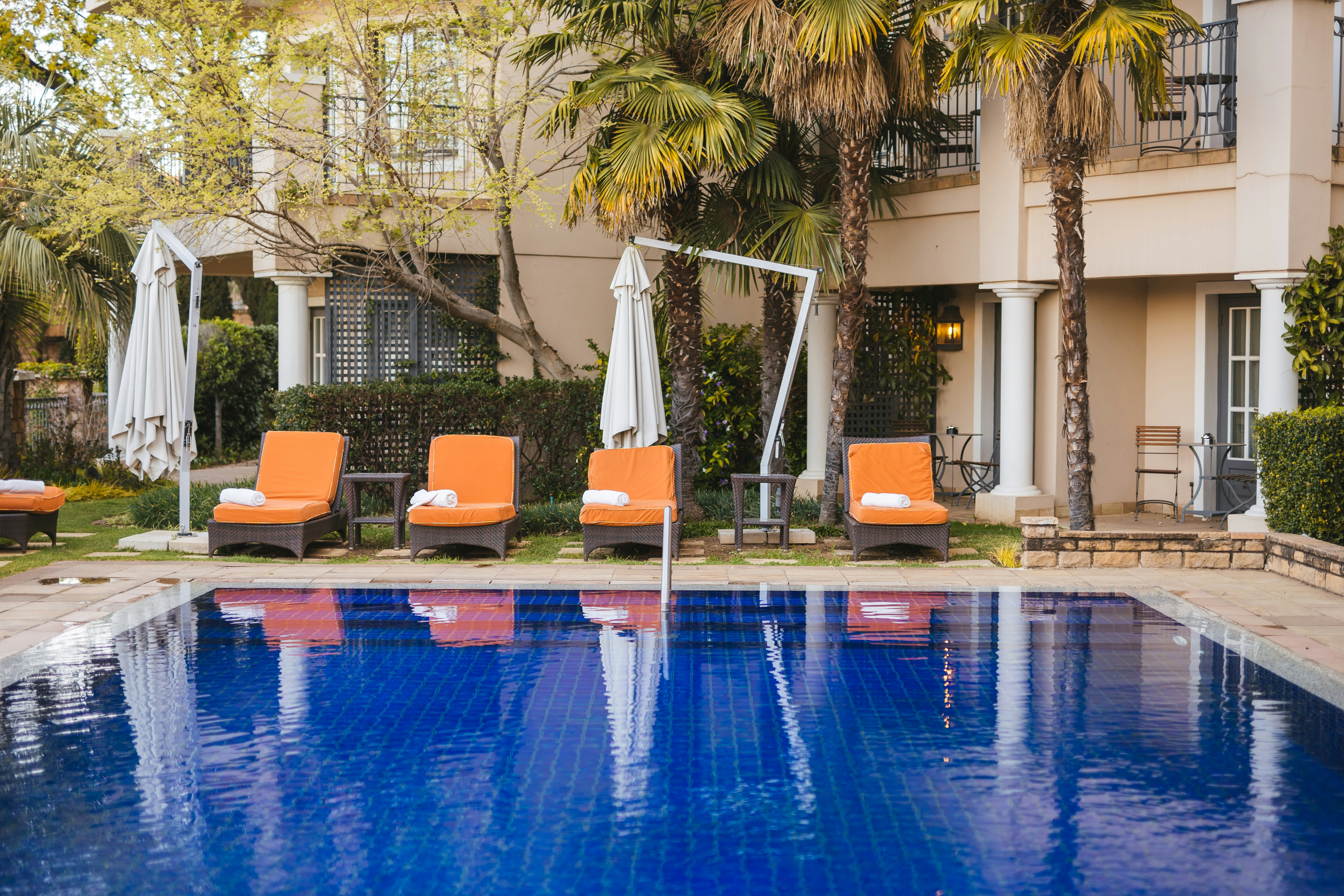 A pool with chairs and umbrellas by a building photo – Free Hotel Image ...