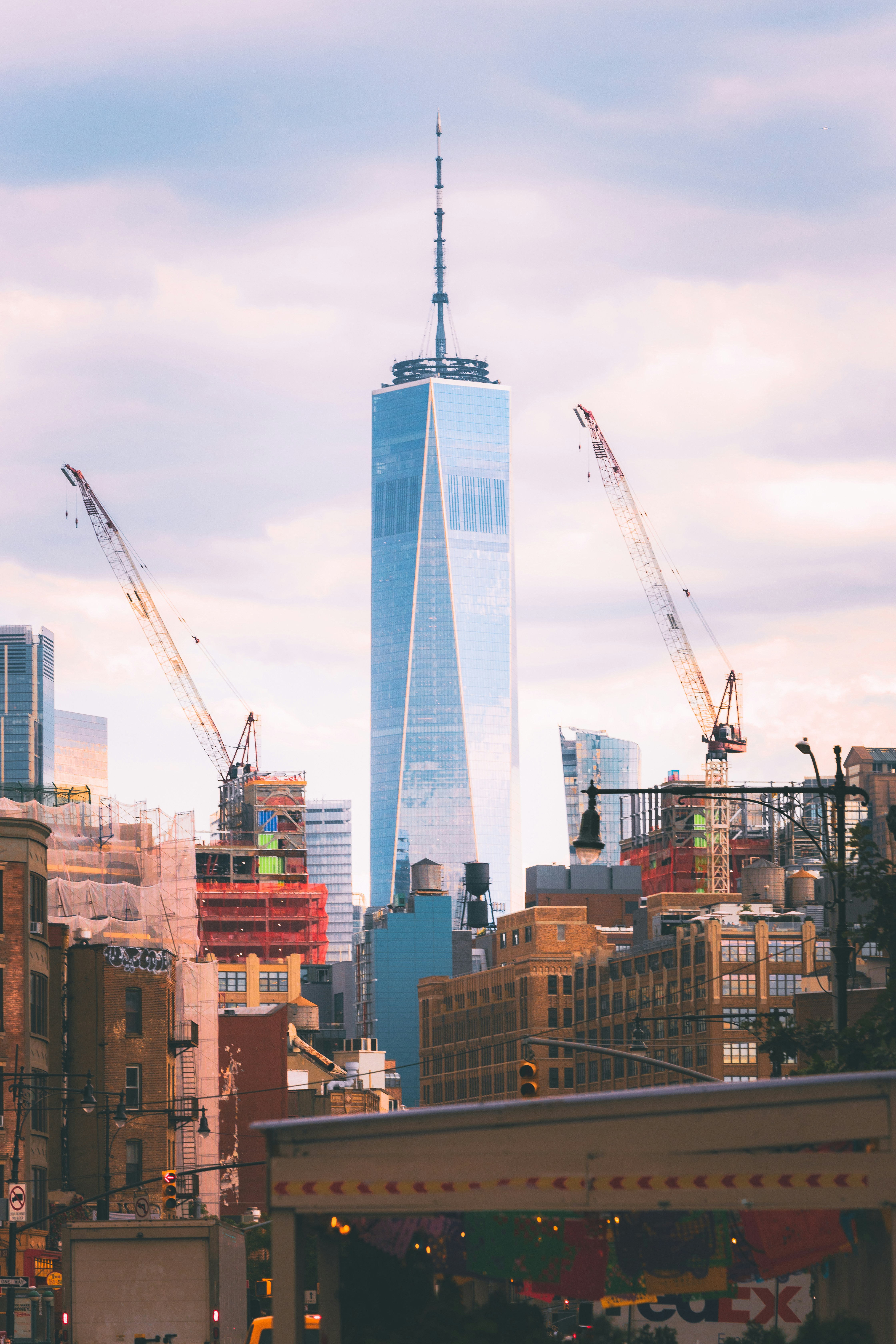 One World Trade Center towers above a bustling cityscape, framed by construction cranes and urban architecture. A testament to resilience and progress.