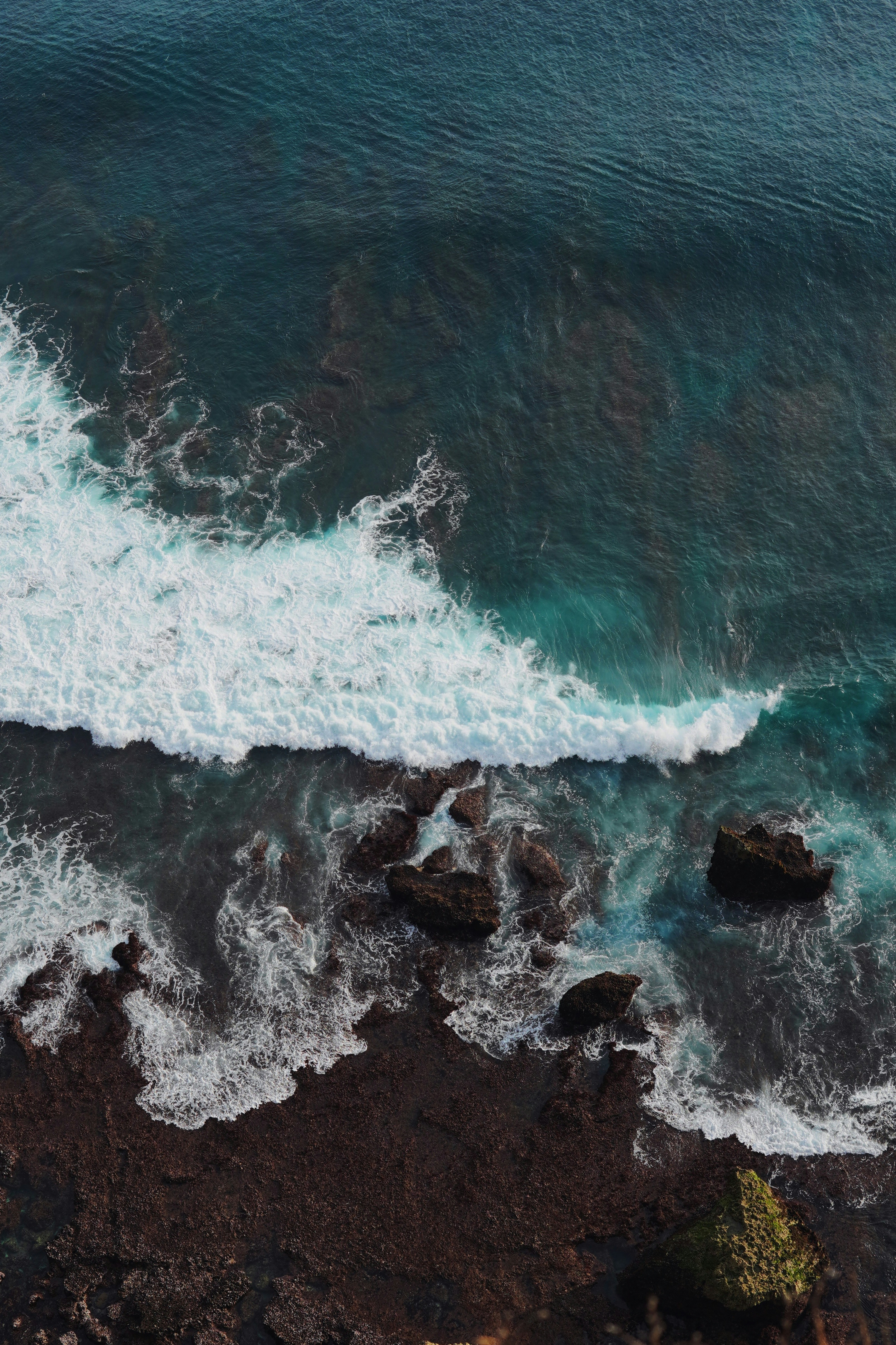 Foamy waves crash against rugged coastal rocks, showcasing the dynamic interaction between land and sea.