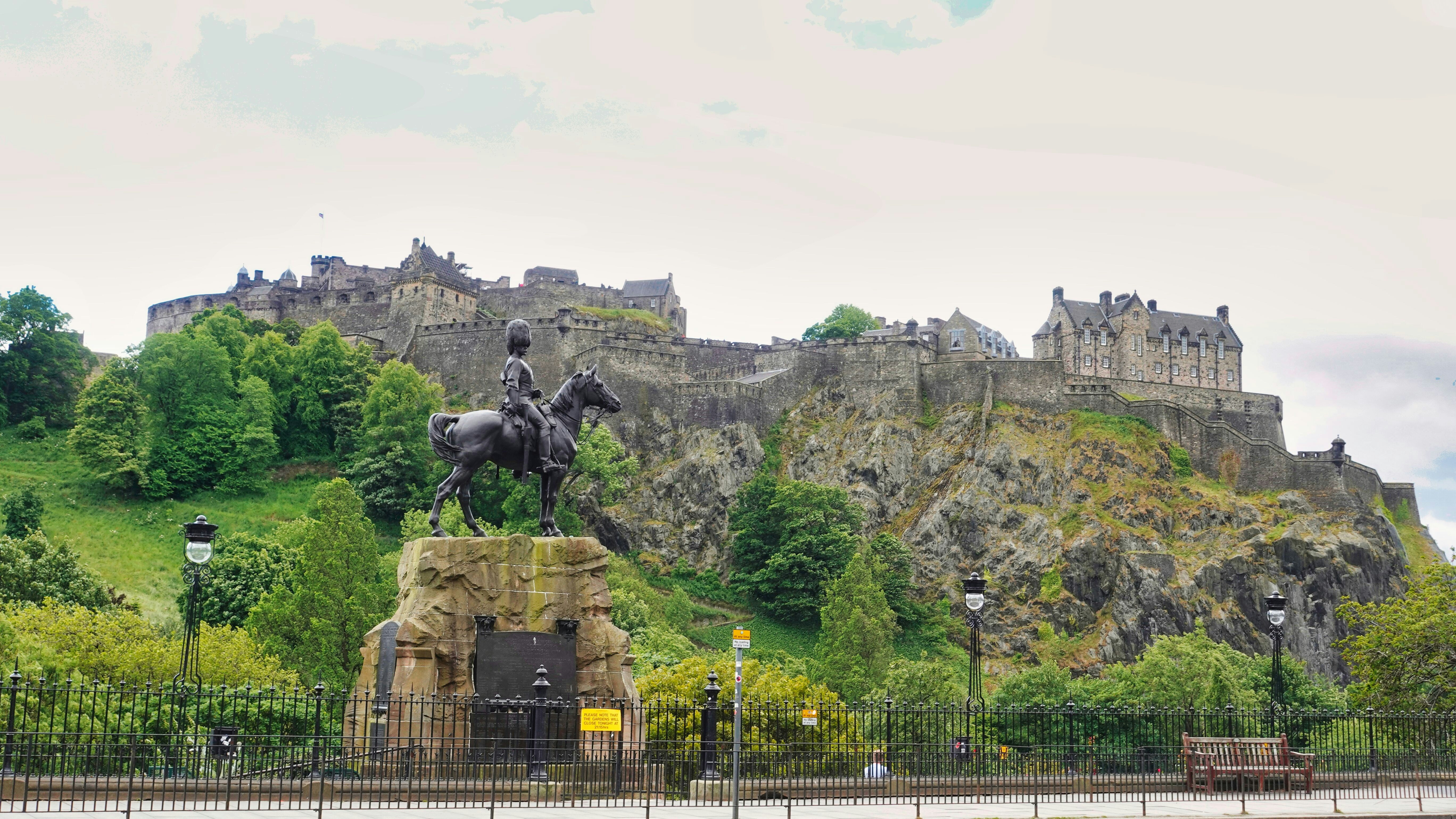 A statue of a person on a horse in front of a castle with Edinburgh ...