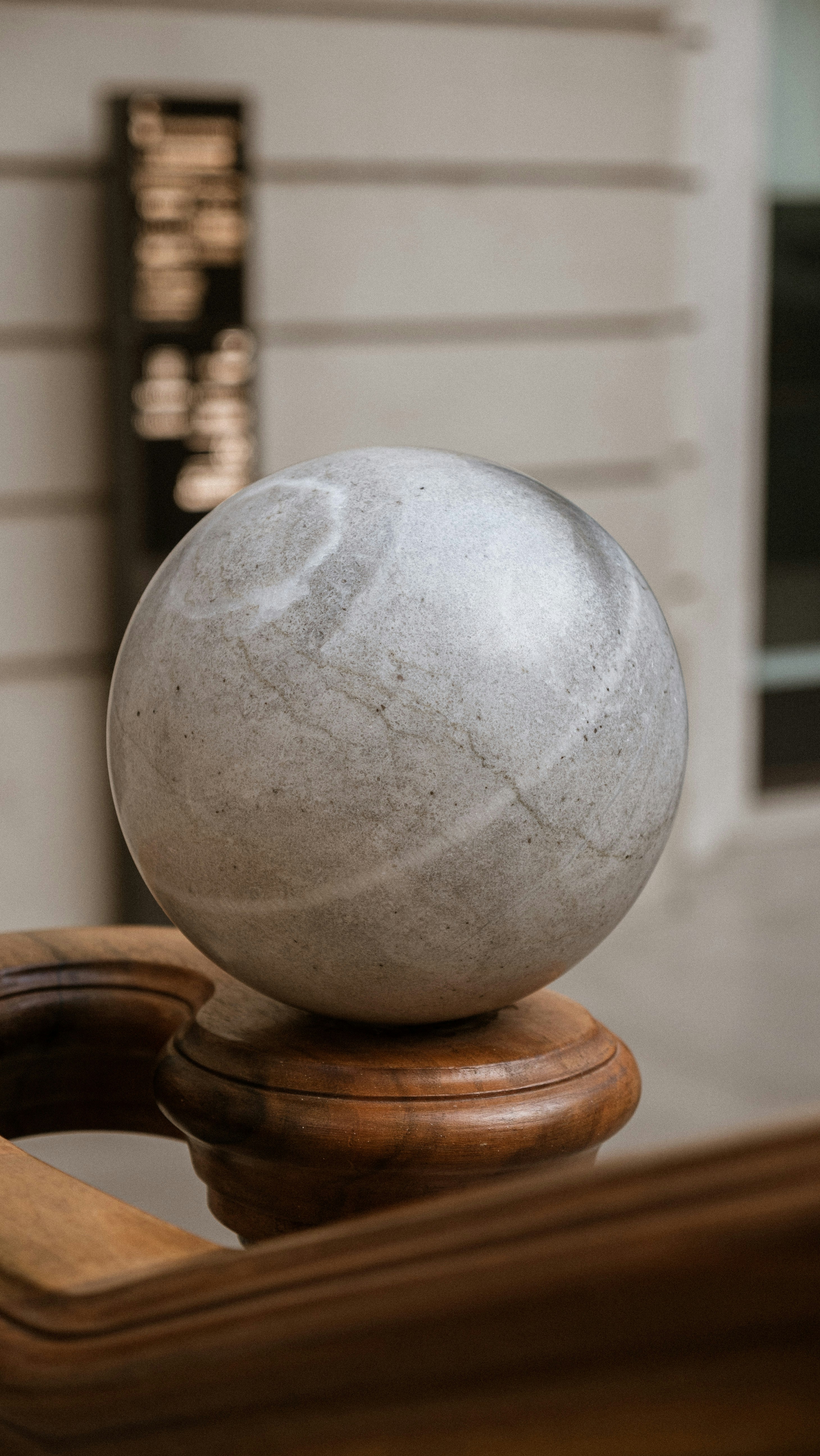 Marble Sphere Resting on a Wooden Railing in Quiet Interior