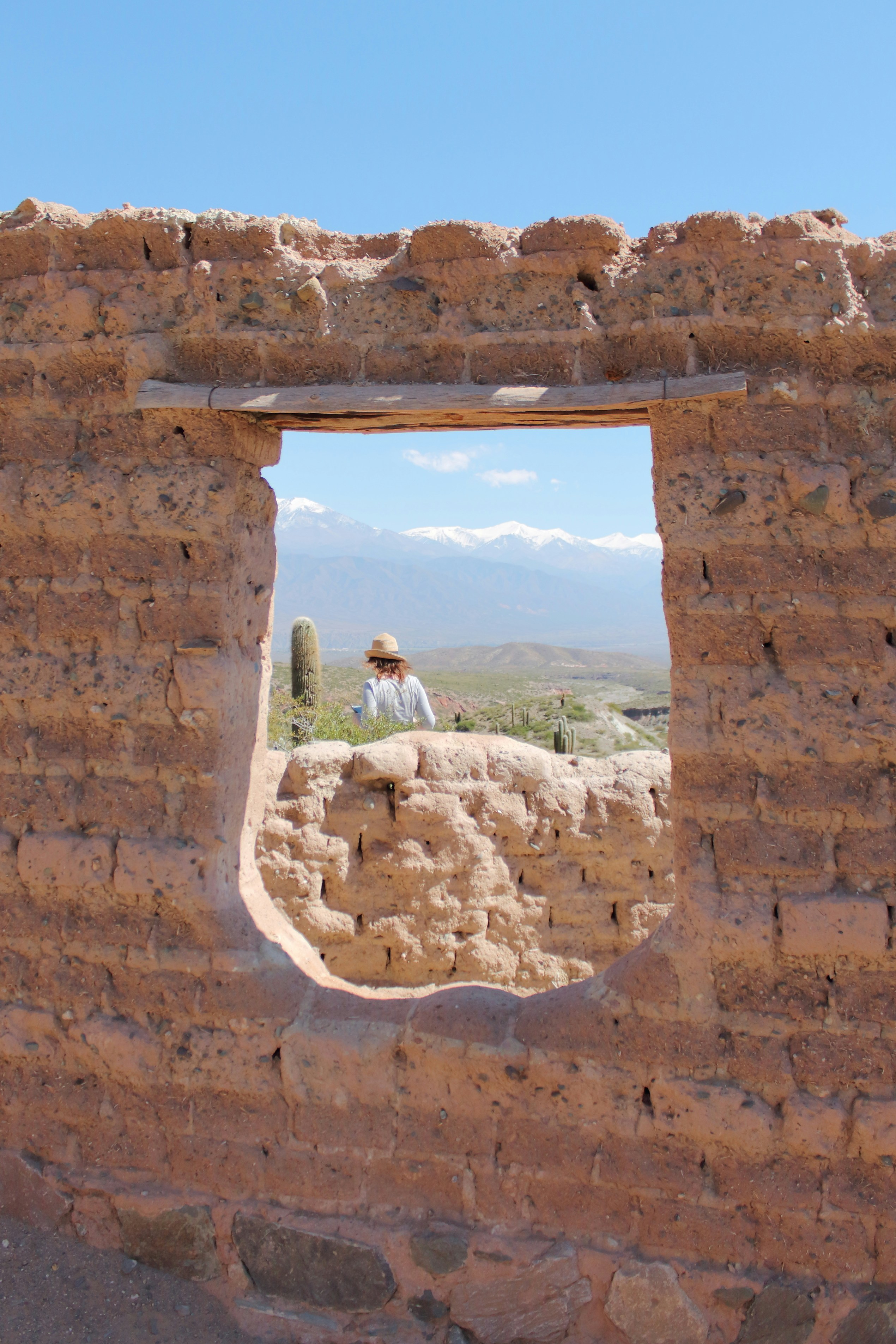 Through the Ruins: A Traveler Framed by Desert Horizons and Snow-Capped Peaks
