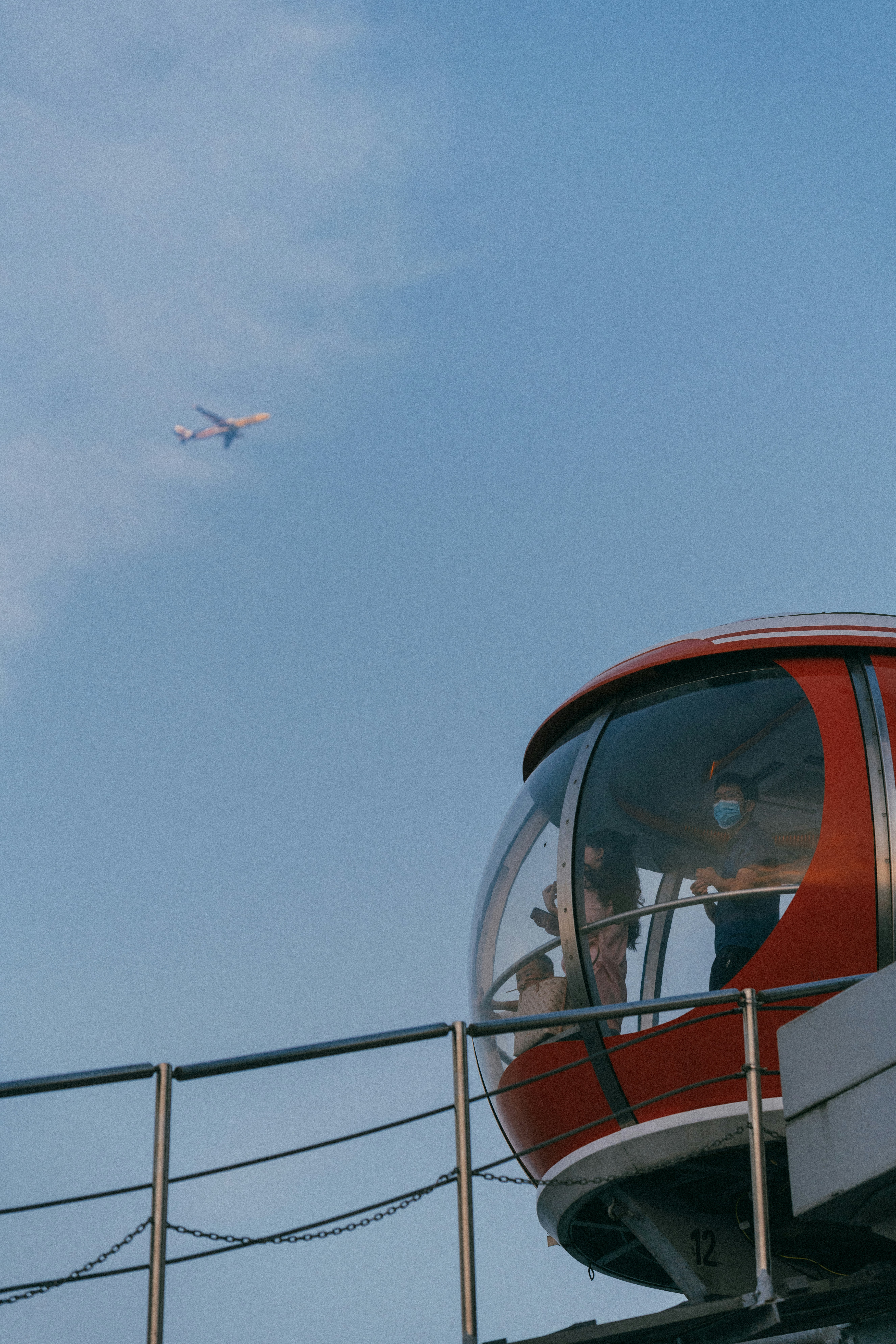 Red Capsule at Skyline Edge: Passengers Inside a Glass Gondola