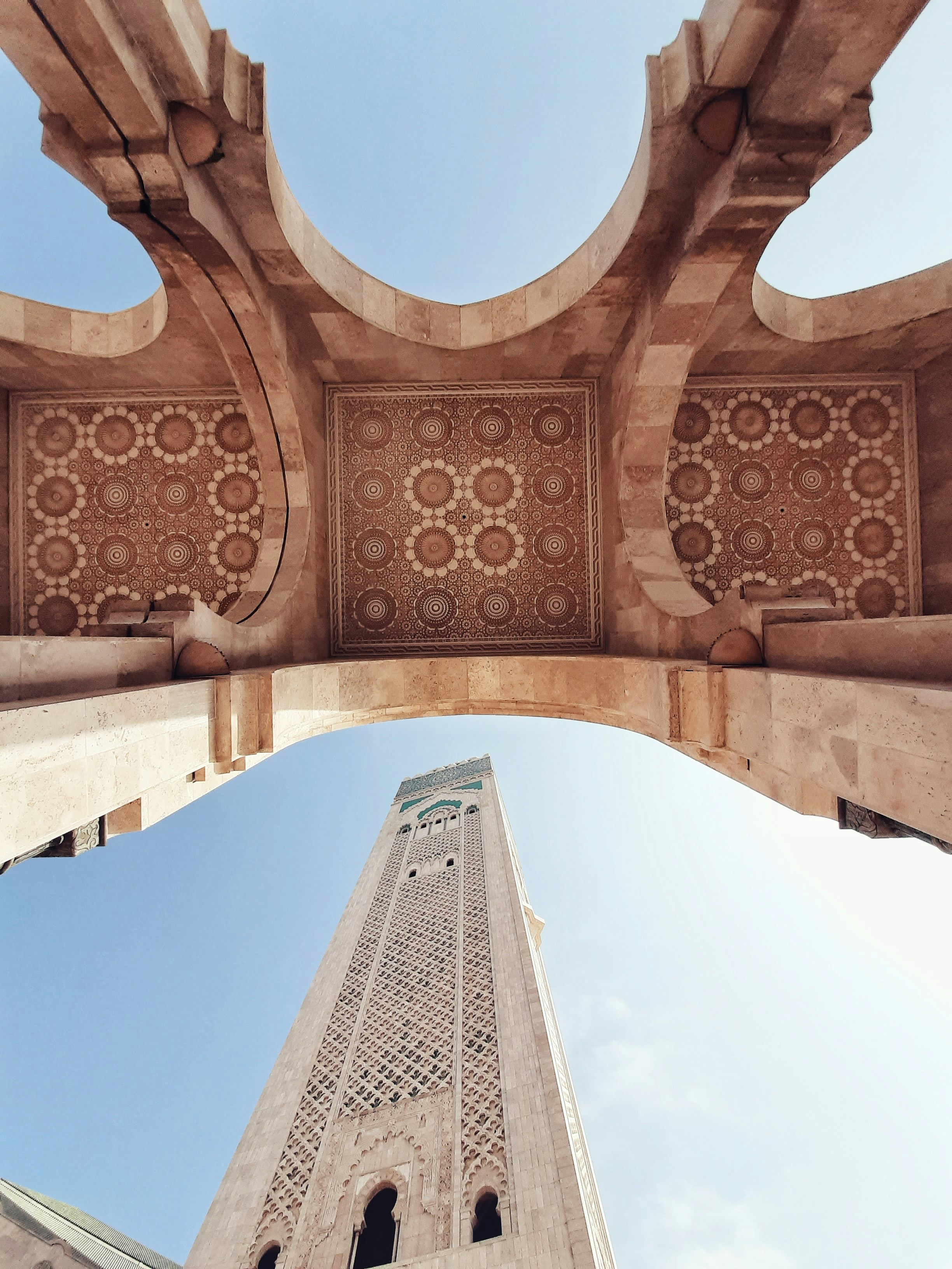 Ornate arches frame the towering minaret of Hassan II Mosque against a clear blue sky.