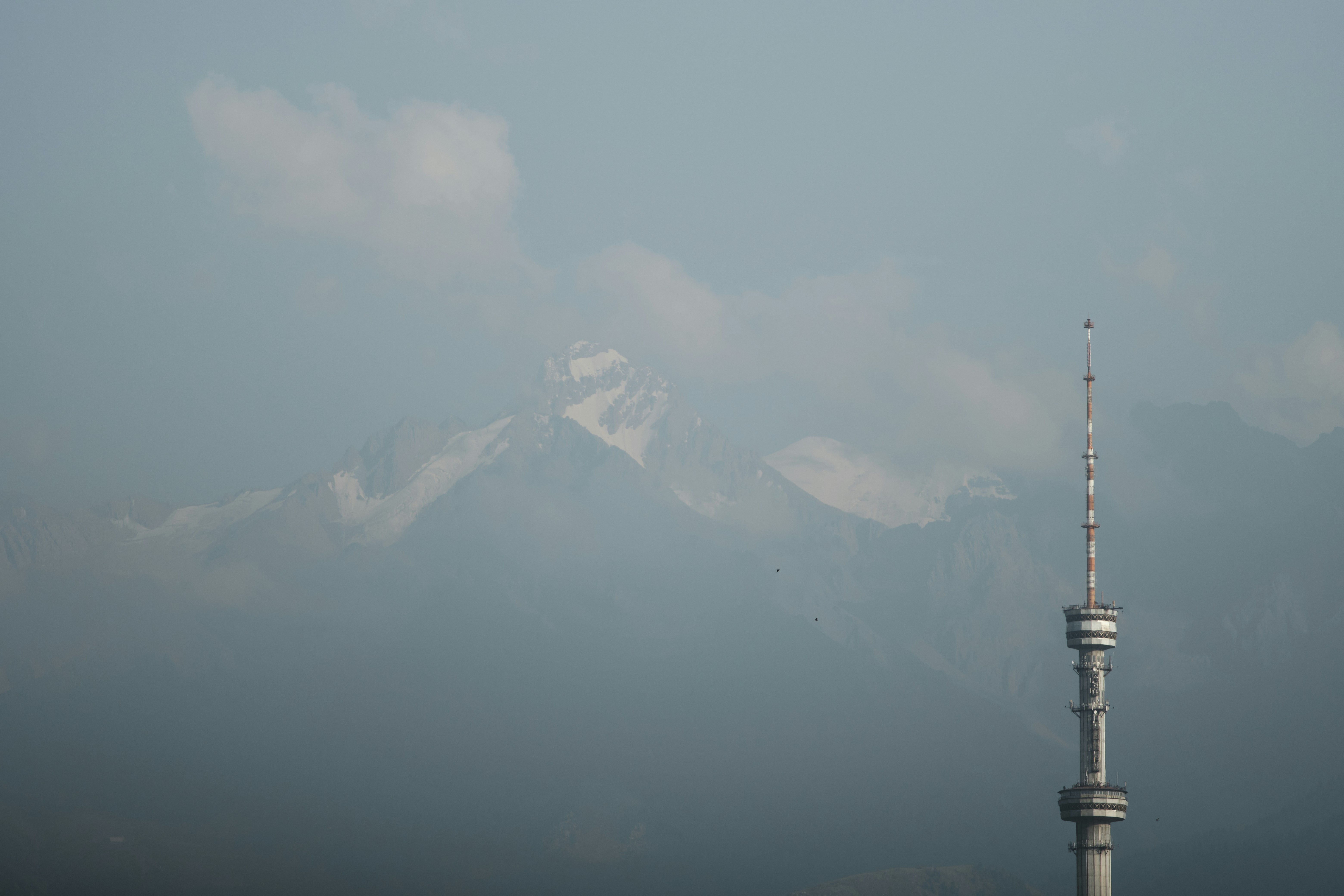 Ridge and Mast: Snow Peaks Framed by a Skyline Tower