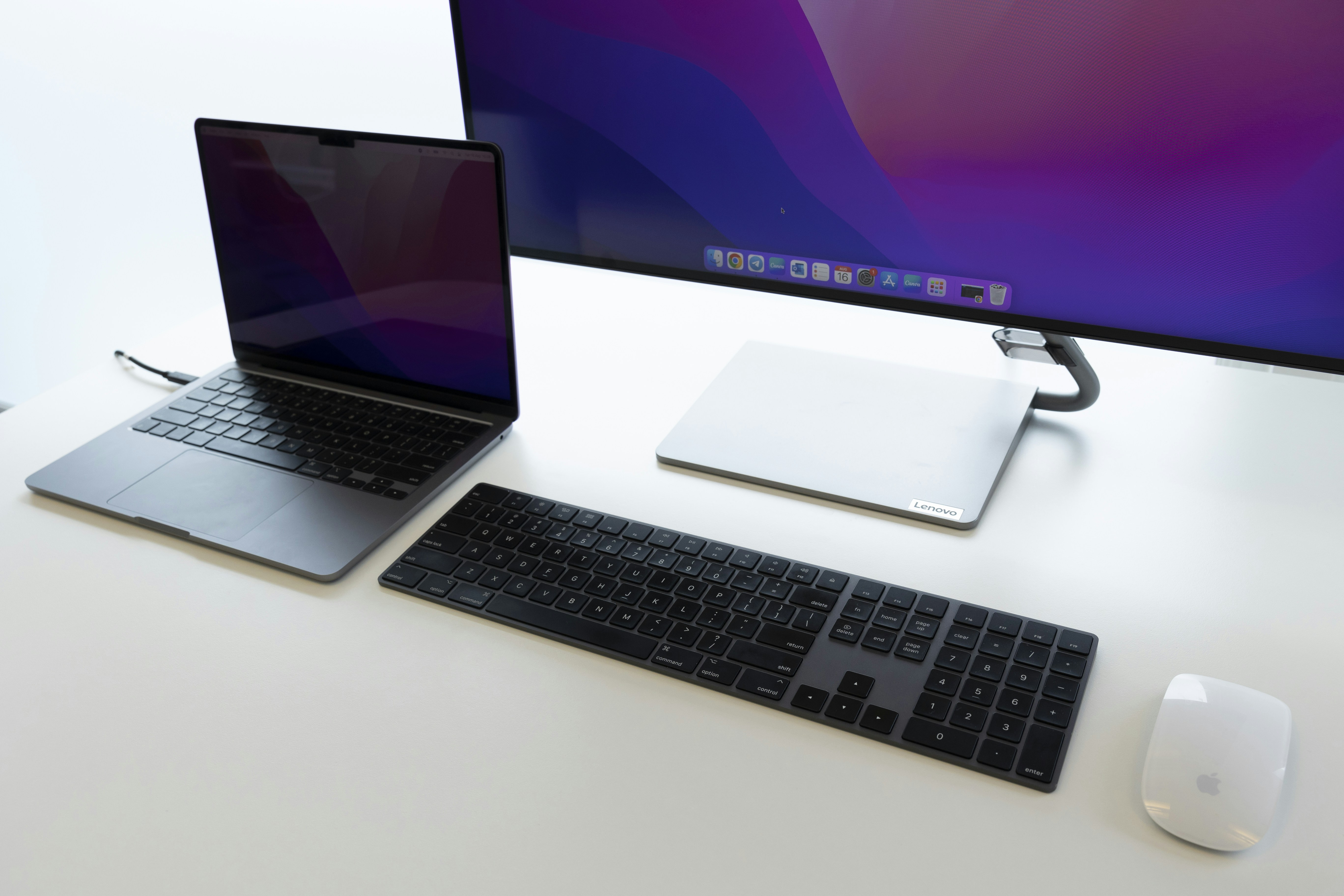Sleek laptop and monitor setup featuring a minimalist keyboard and mouse, designed for productivity and modern aesthetics.