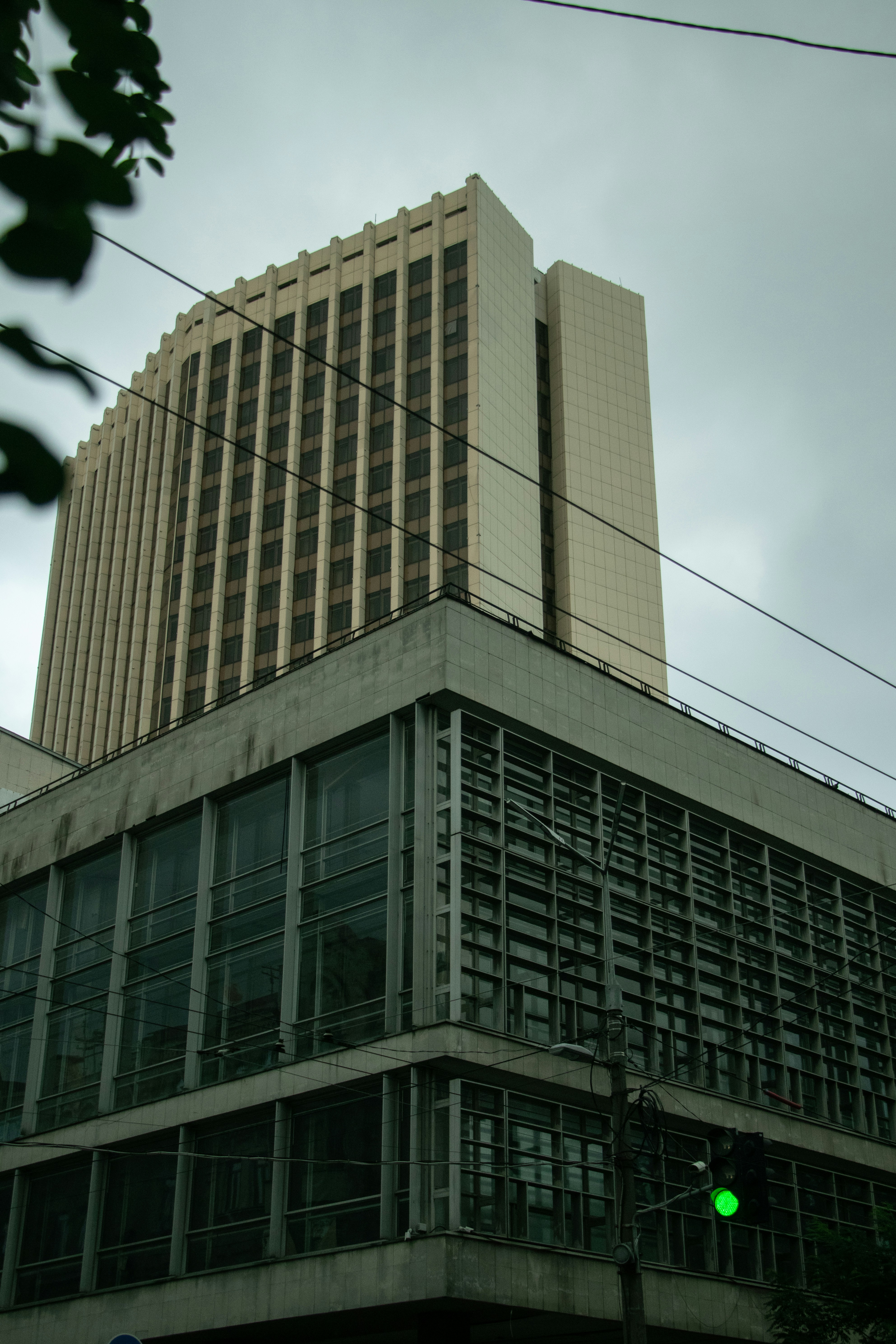 Beige Monolith Rising Over a Glass Grid in Overcast Light