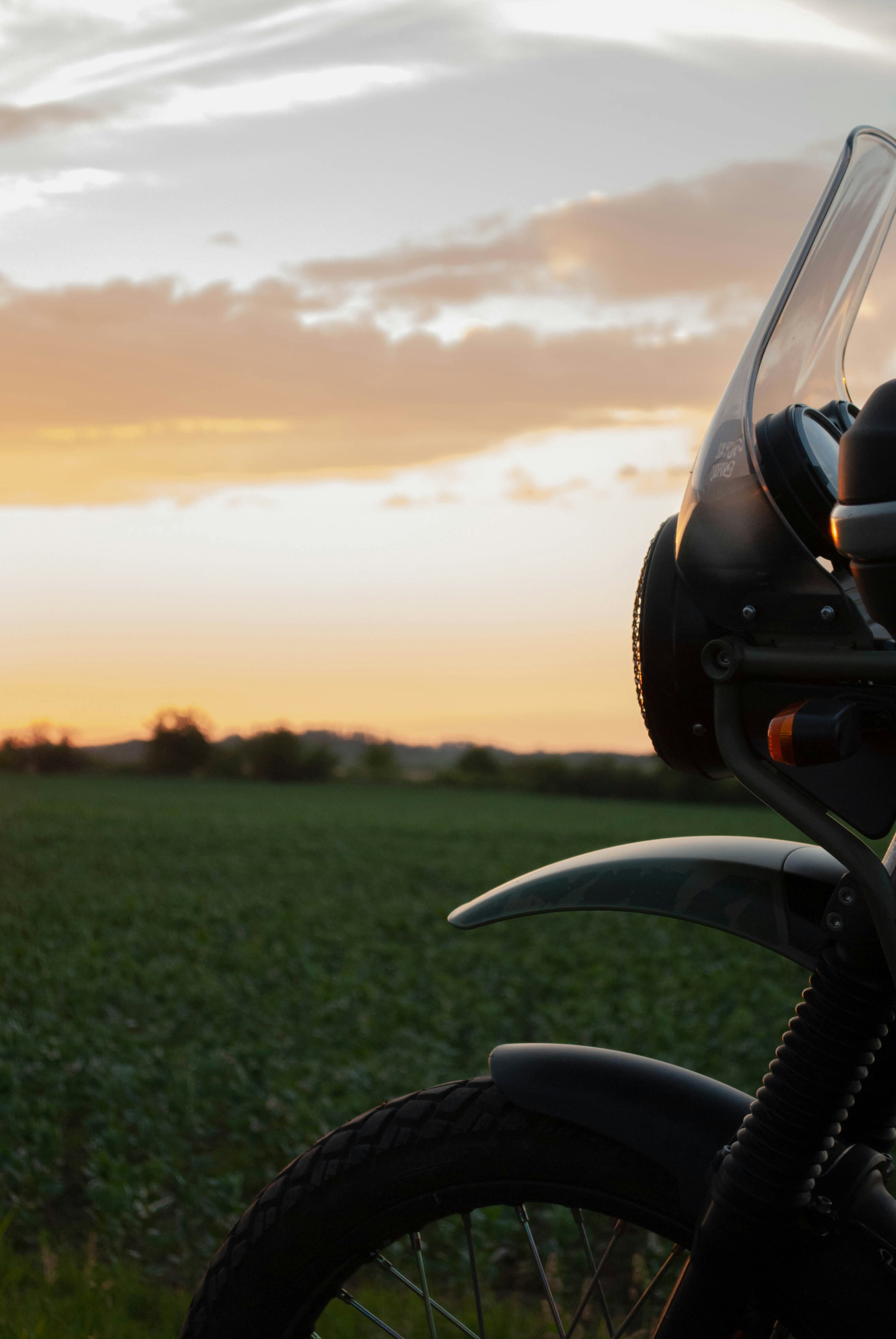 Dusk Edge: The Motorcycle's Windshield Framing a Golden Field Horizon