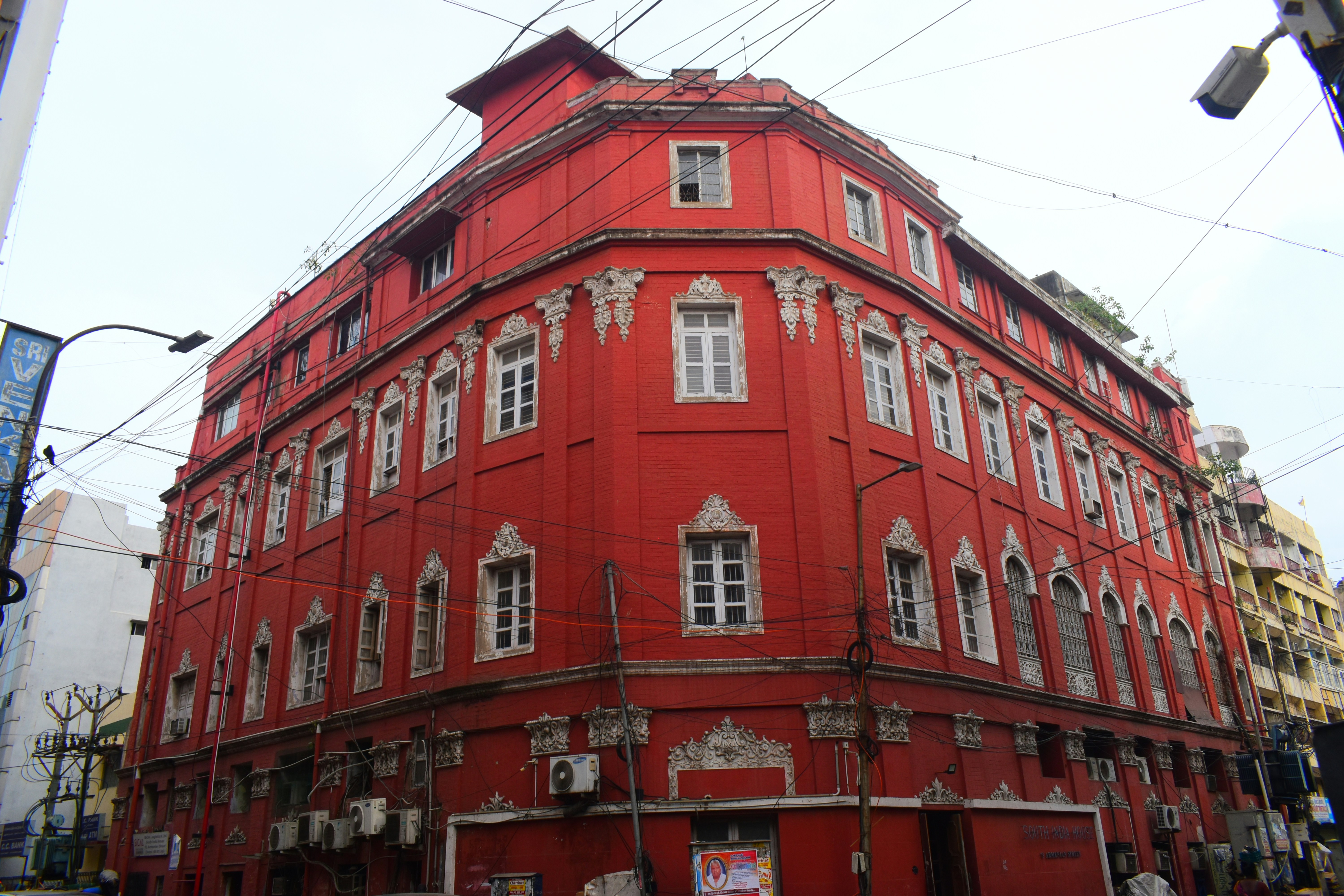Crimson Corner Facade: Ornate Red Brick Edifice in an Urban Tangle