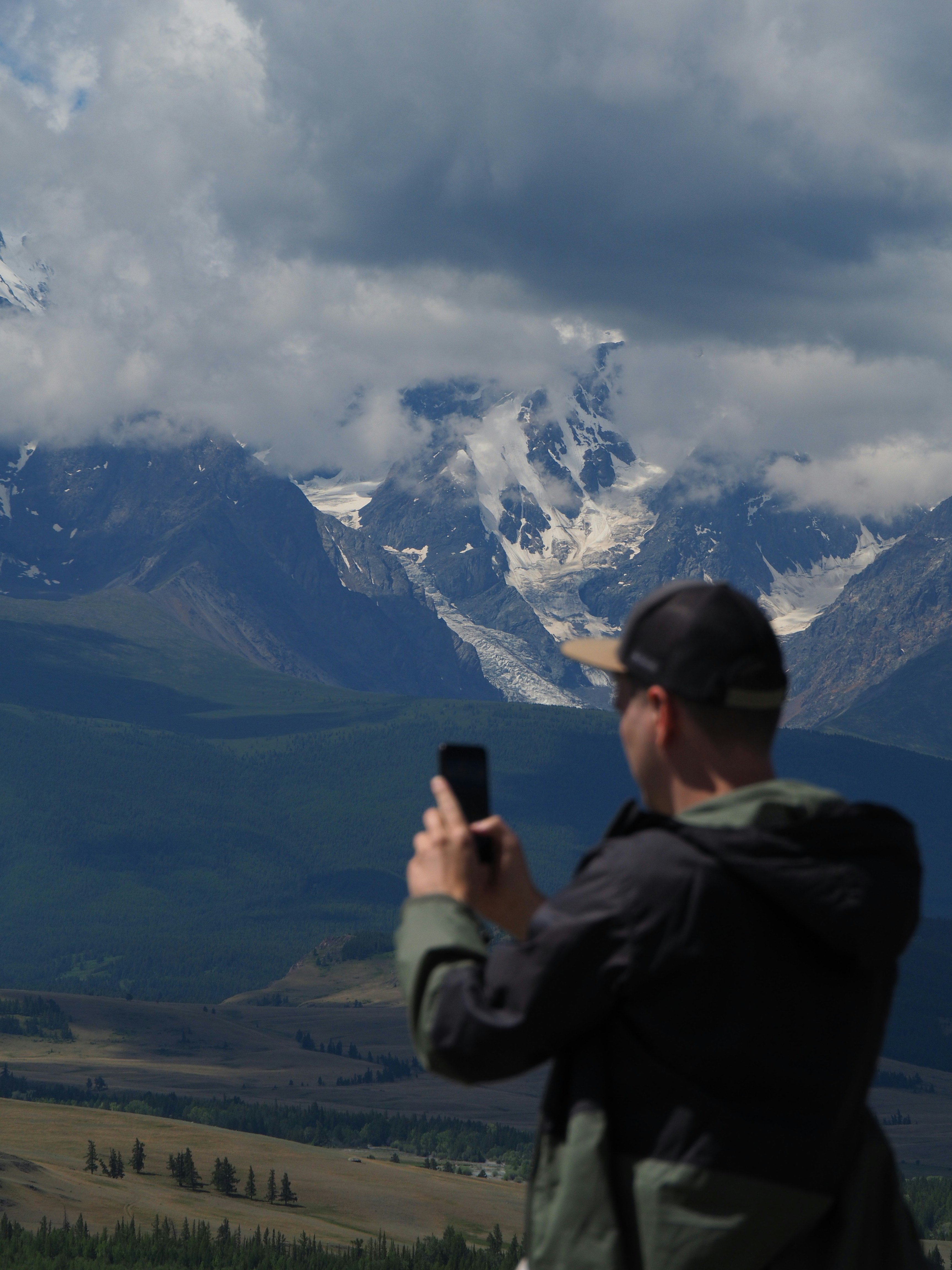 Shutter in the Saddle: A Hiker Frames Snow-Crowned Peaks with a Pocket View