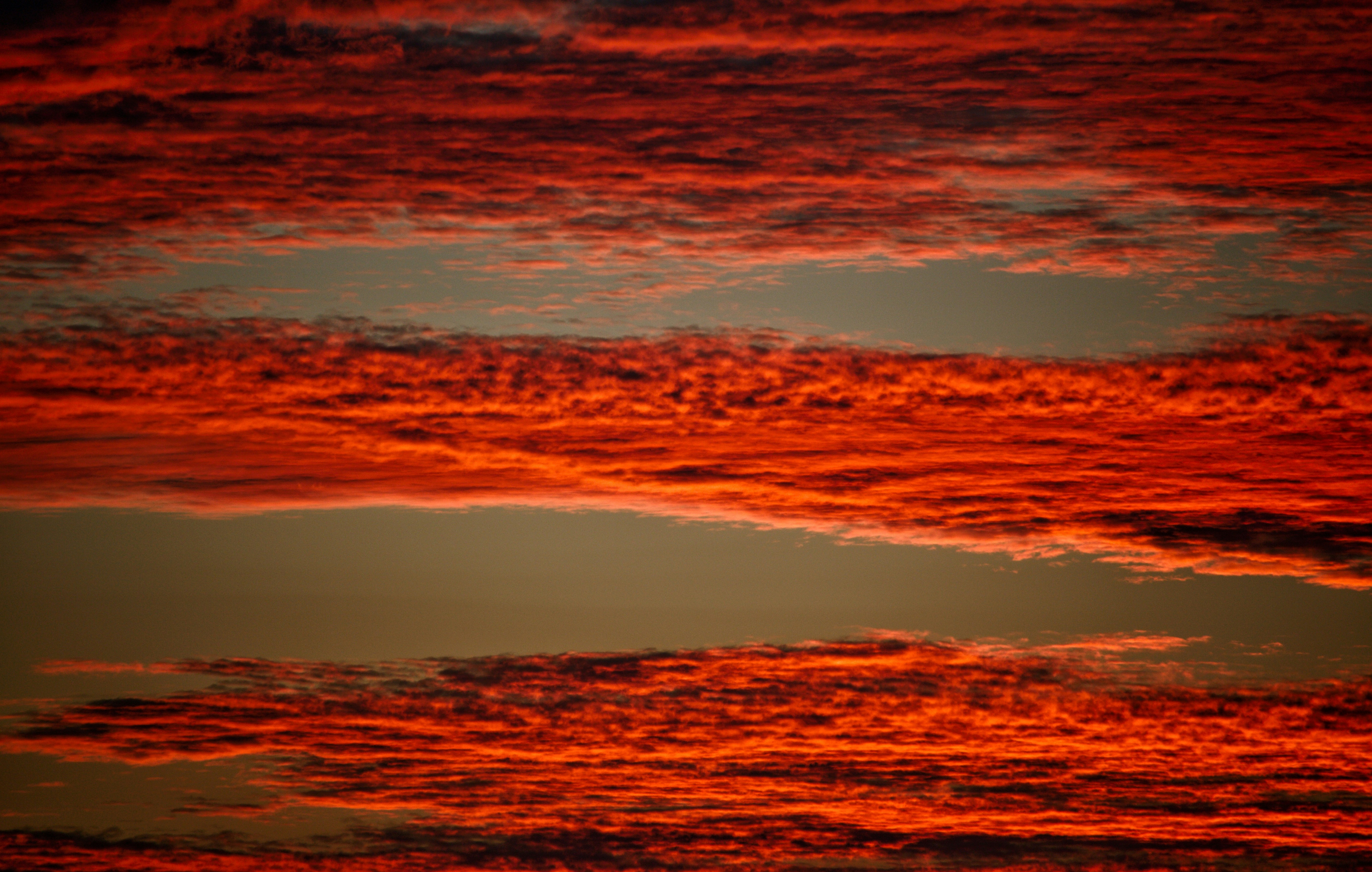 Vibrant clouds ablaze with shades of red and orange stretch across the evening sky, creating a dramatic backdrop.