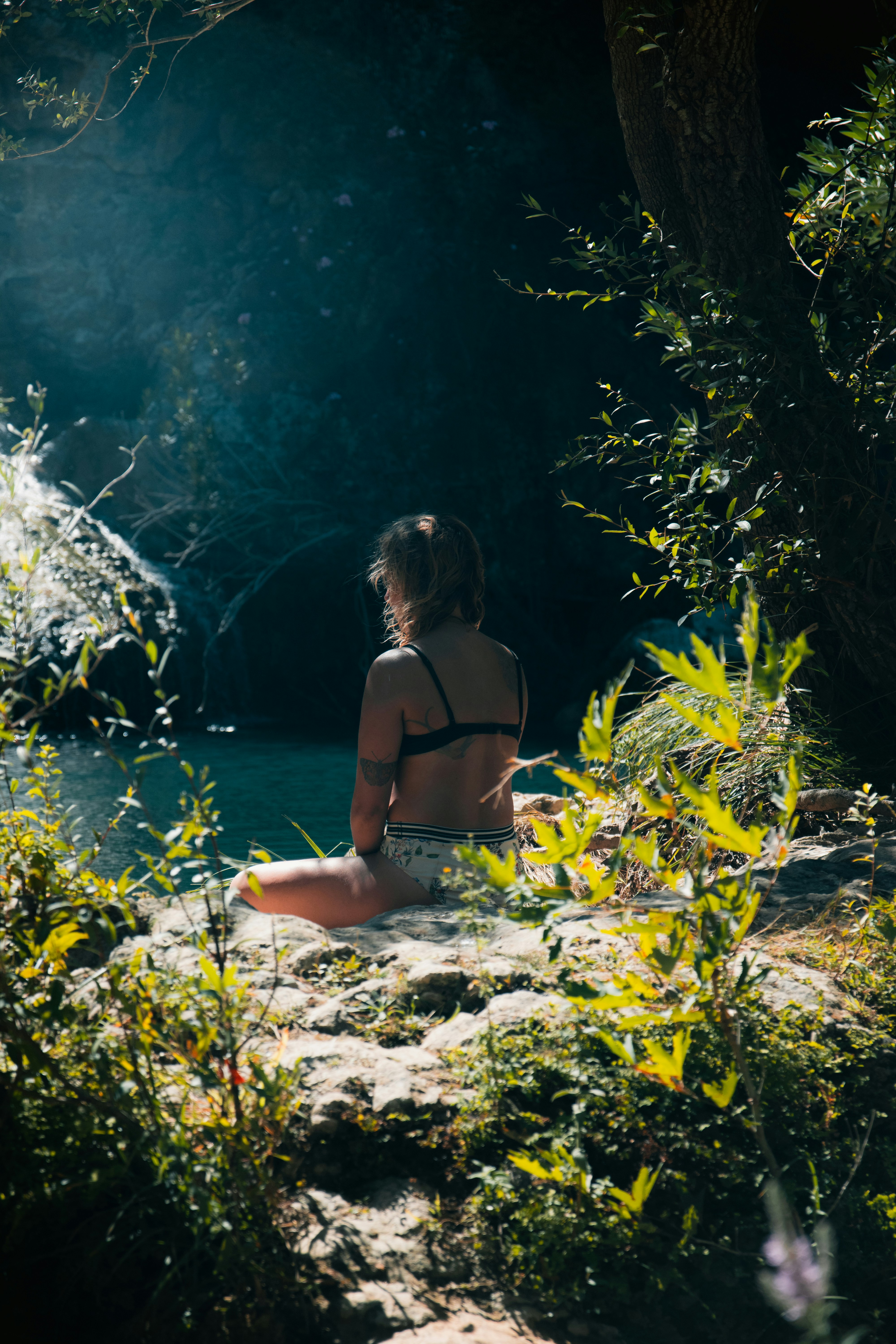 a person sitting on a rock by a river