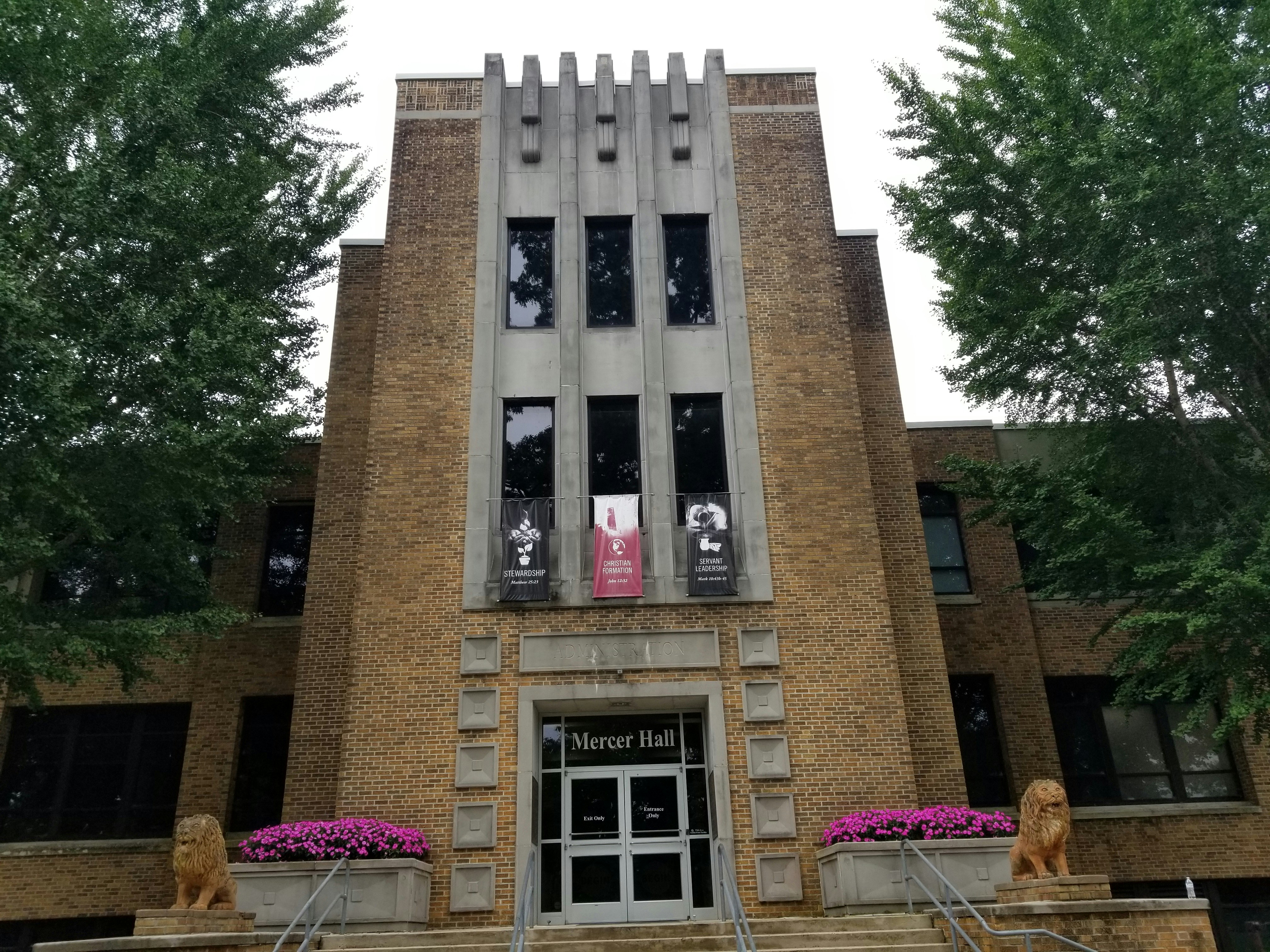 Mercer Hall Facade: Brick Tower and Bannered Entrance Framed by Citrus Blossoms