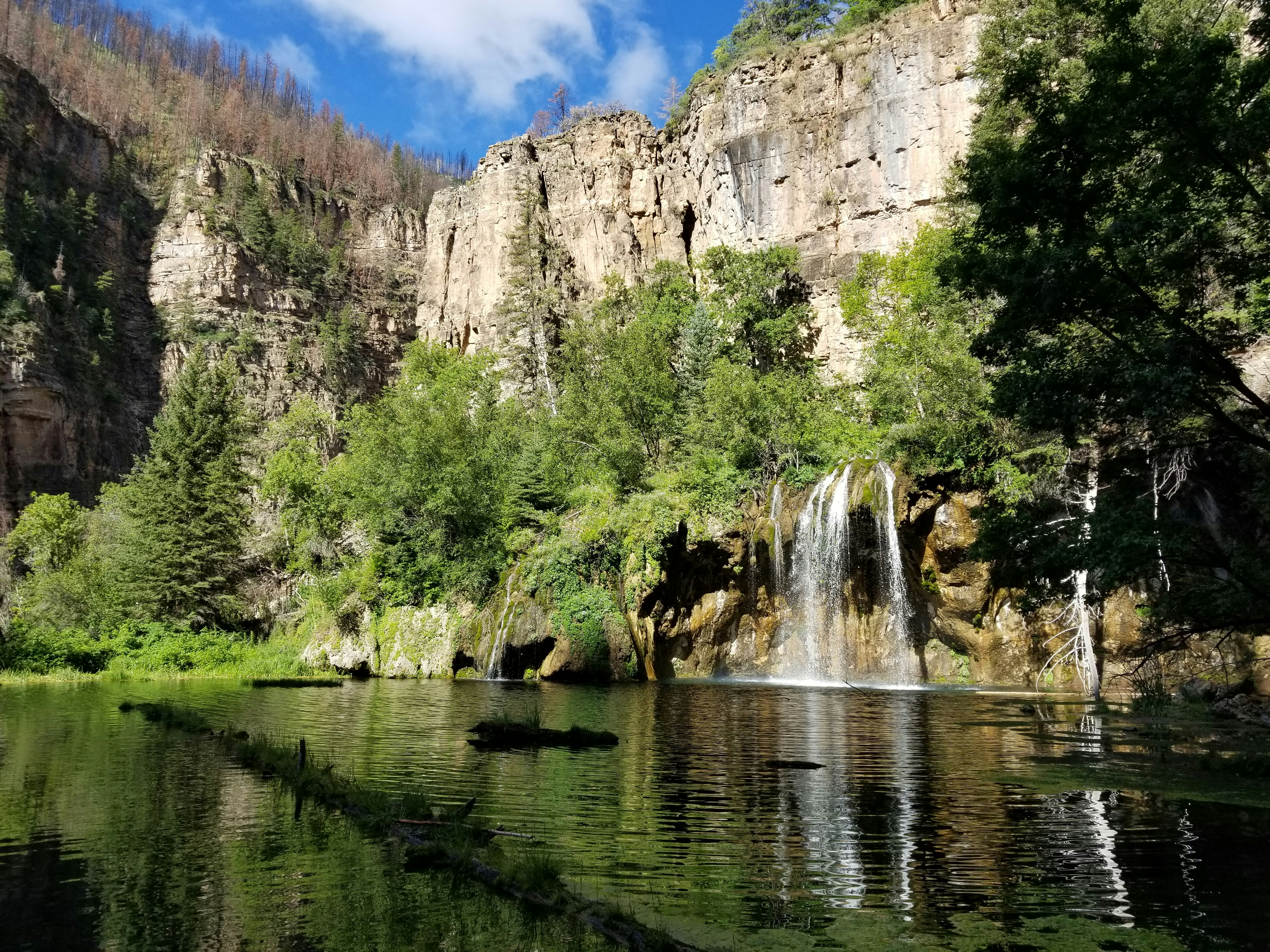 Cascade in a Quiet Gorge: Sunlit Falls Across a Serene Lake