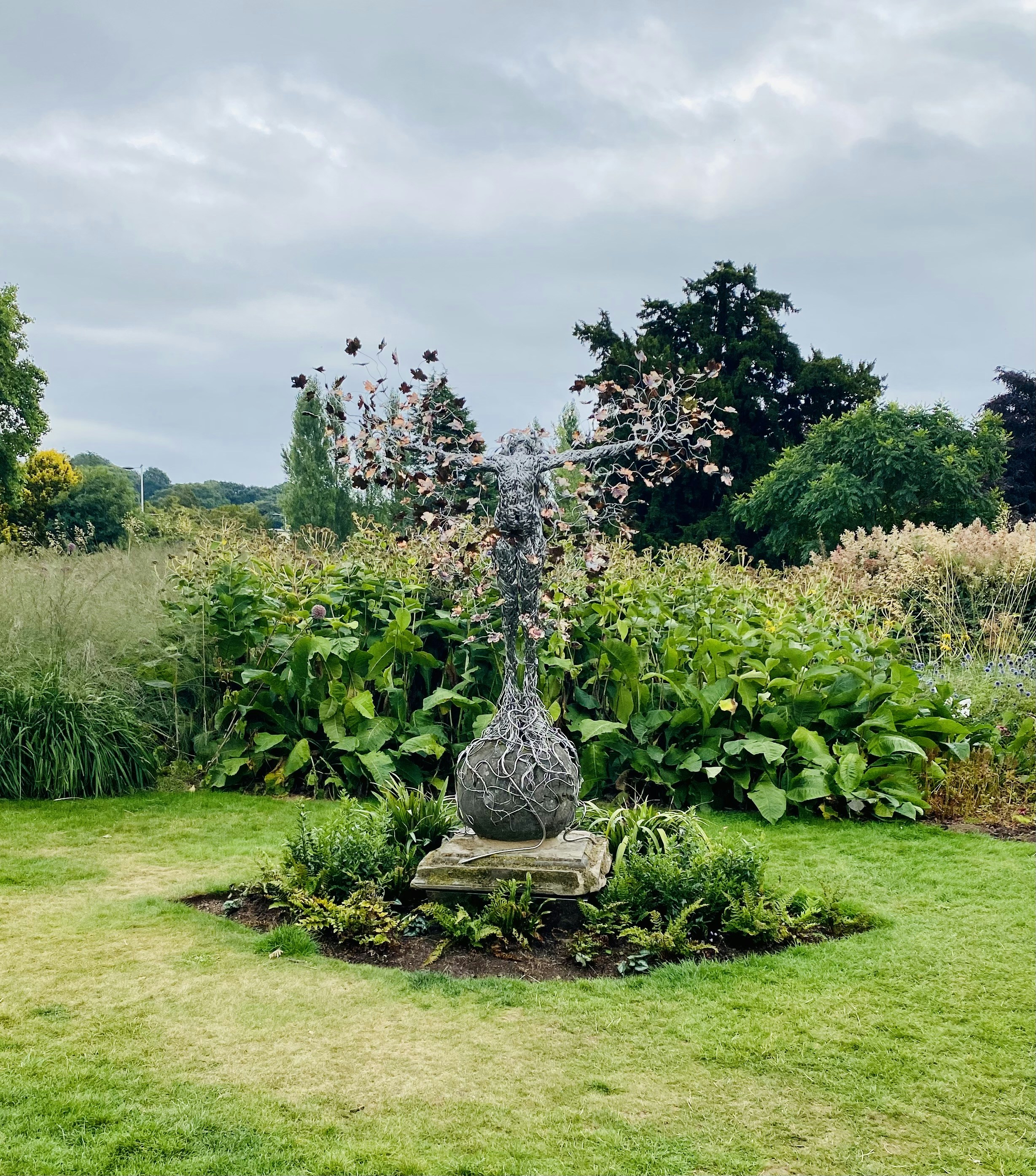 Iron Tree on a Stone Plinth: Garden Centerpiece Amid Verdant Hedges