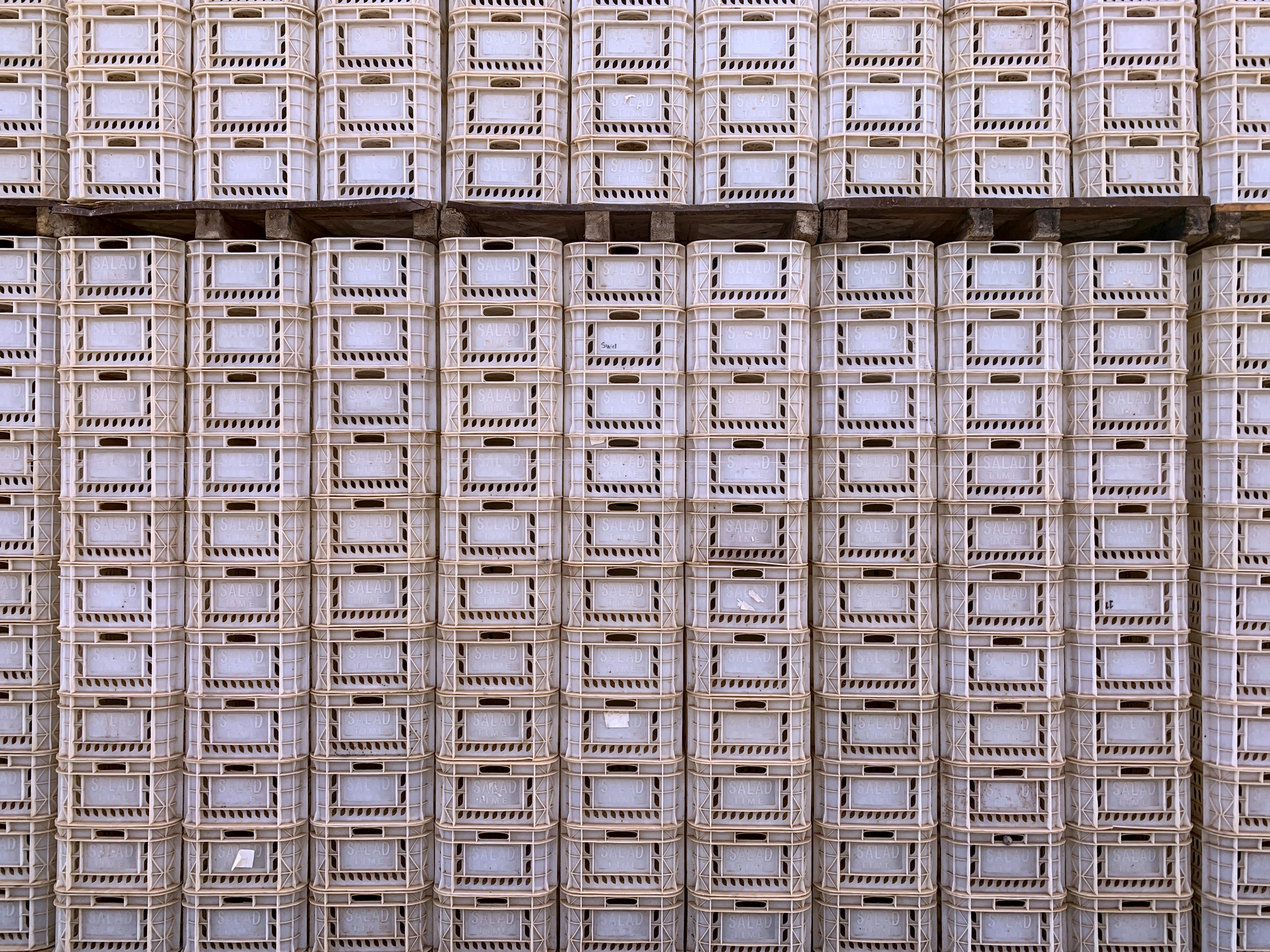 A meticulously arranged wall of storage crates, showcasing uniformity and industrial design. The pattern highlights the efficiency of space utilization.