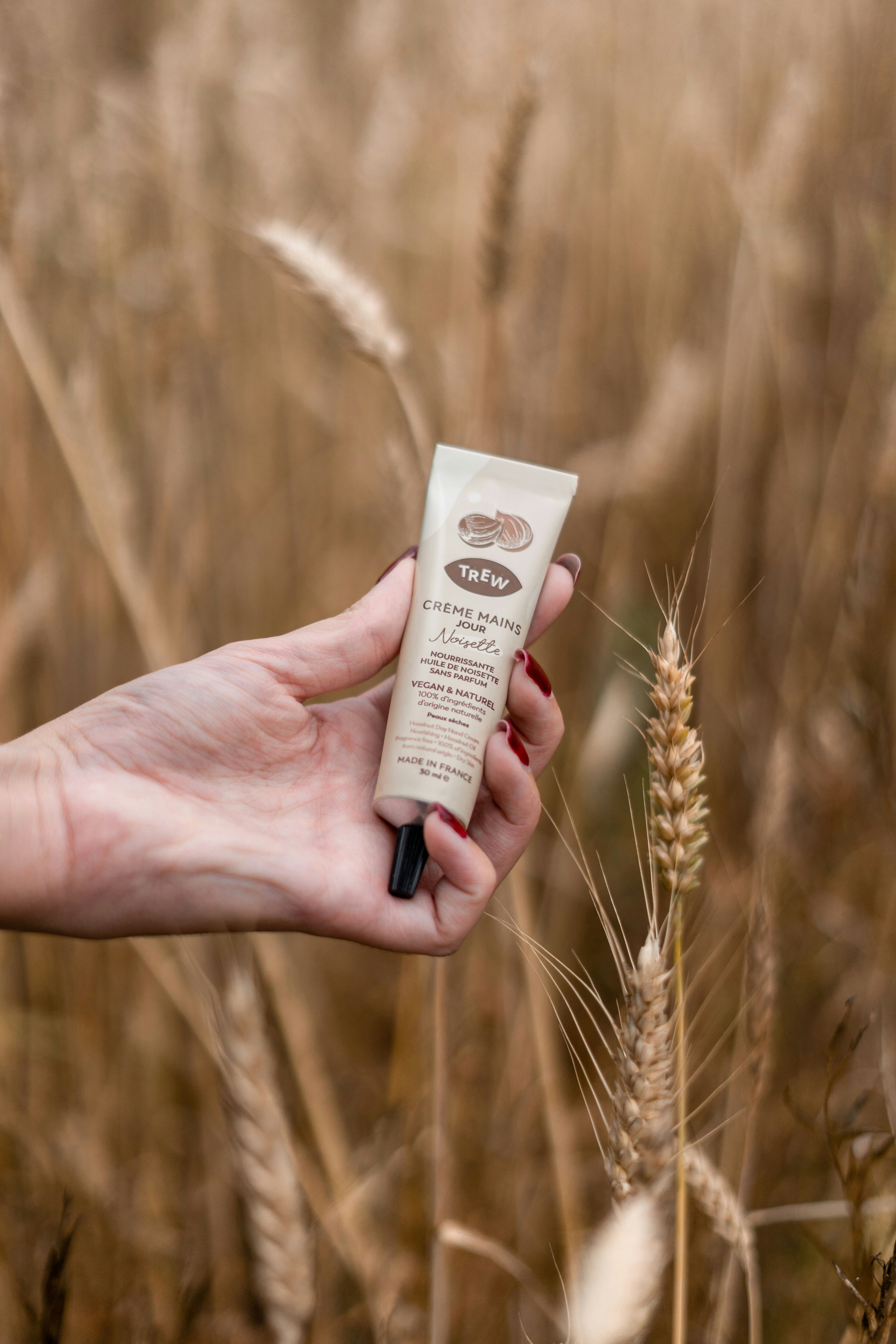 Cream in the Cornfield: hand presents TREW tube amid amber stalks