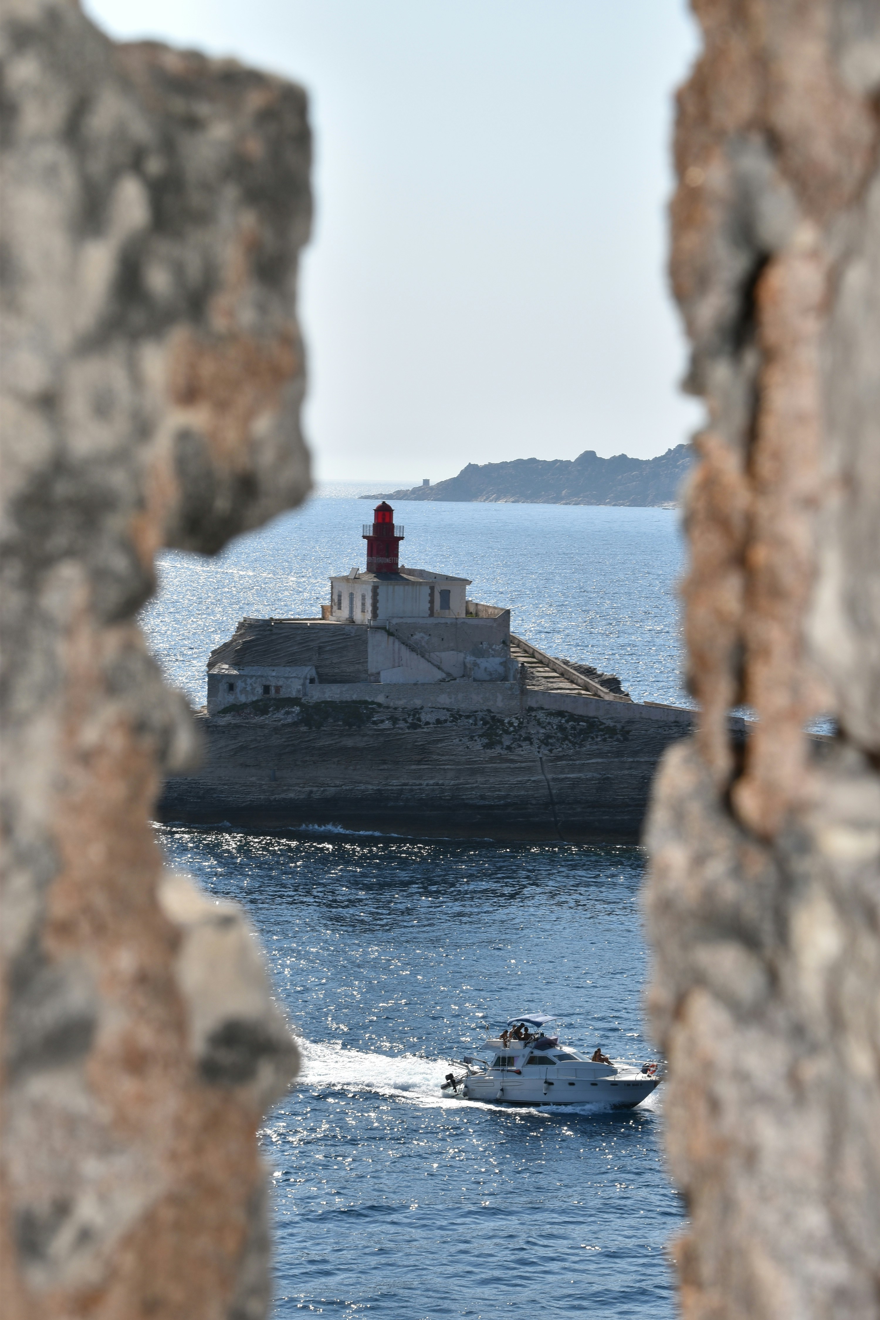 Lighthouse Framed by Seascape Between Weathered Cliffs