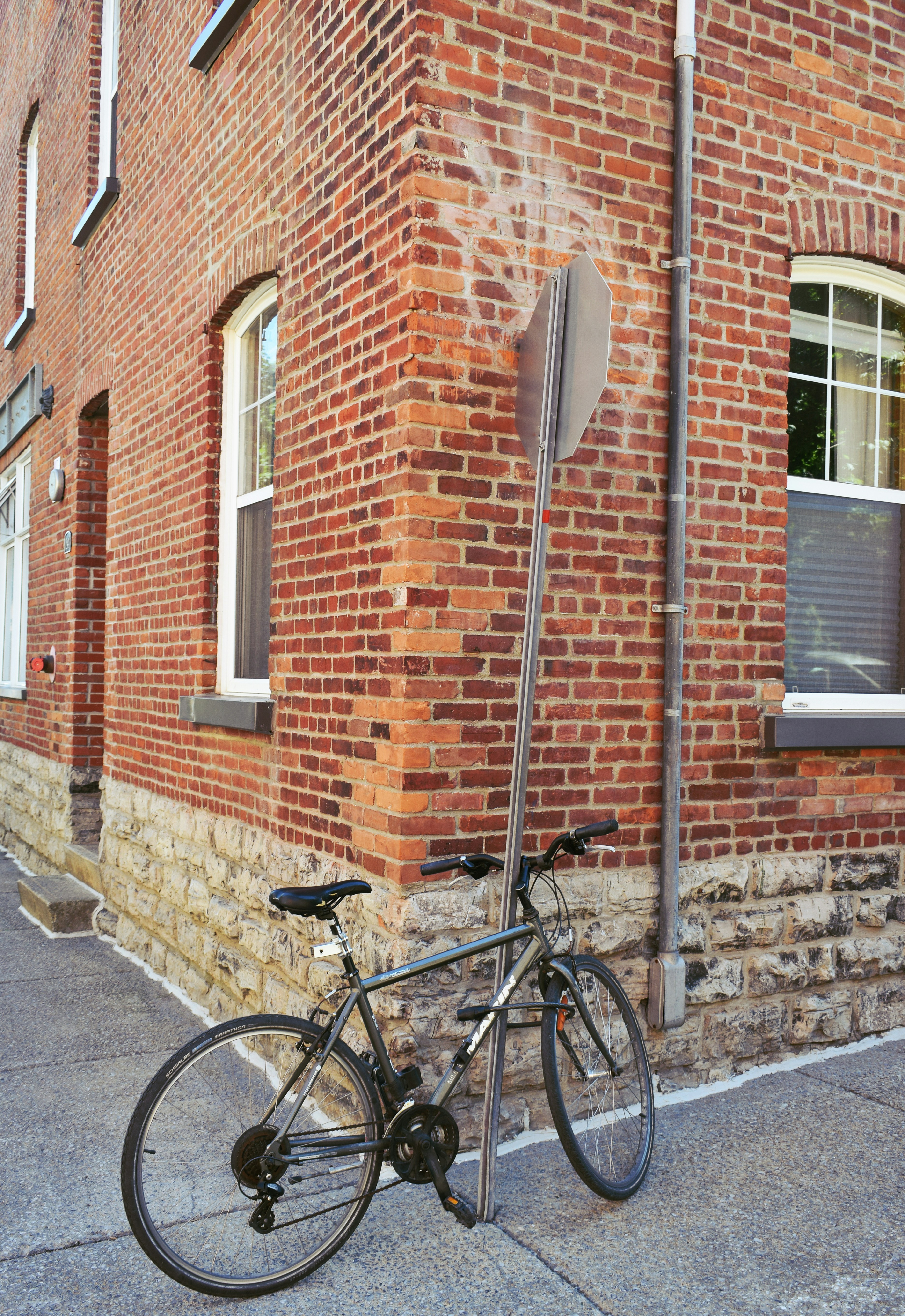Cornered by Brickwork: A City Bicycle Leaning by a Red Brick Street Corner