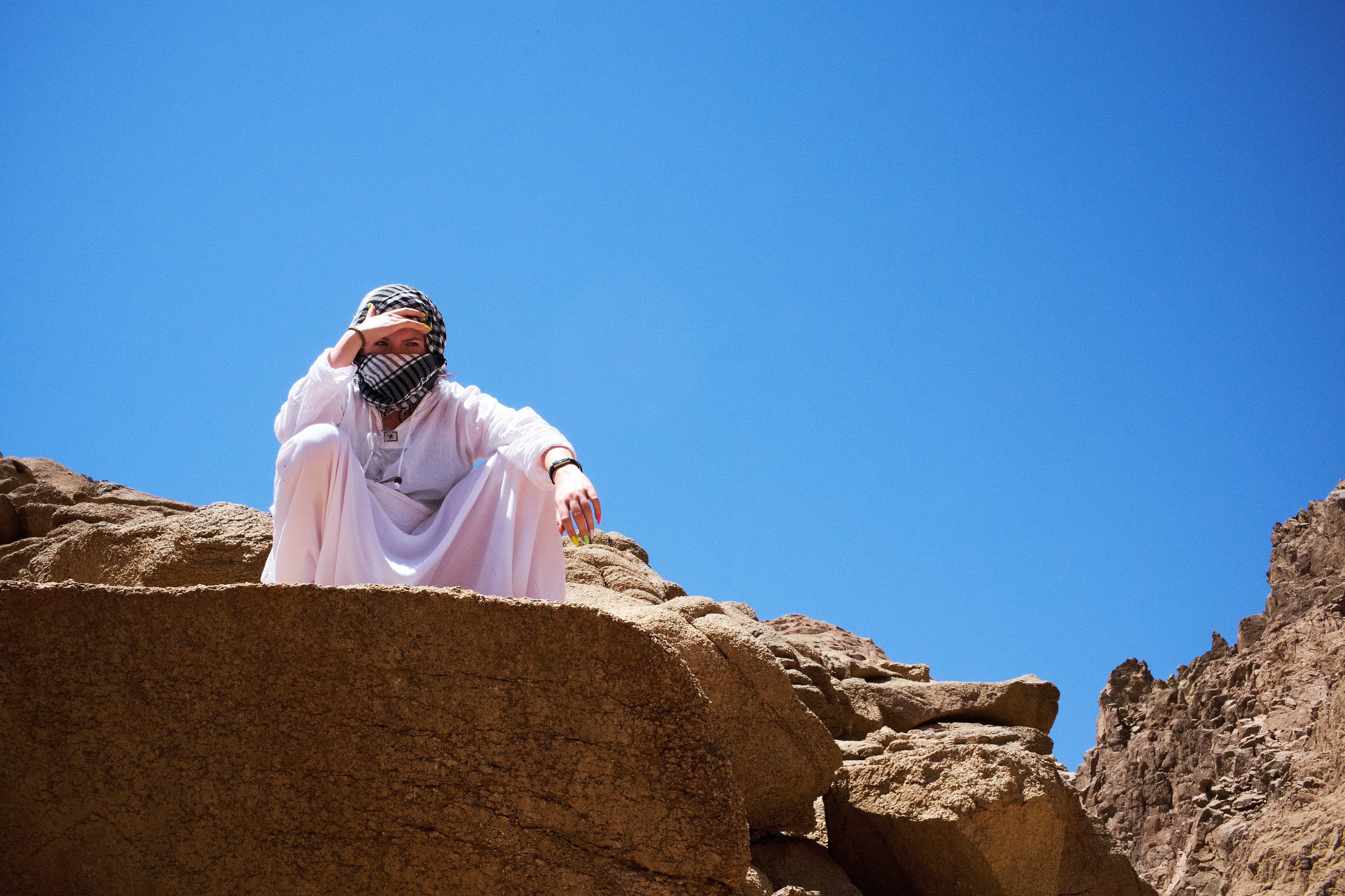 A man in a white robe and head covering standing on a rock photo – Free ...