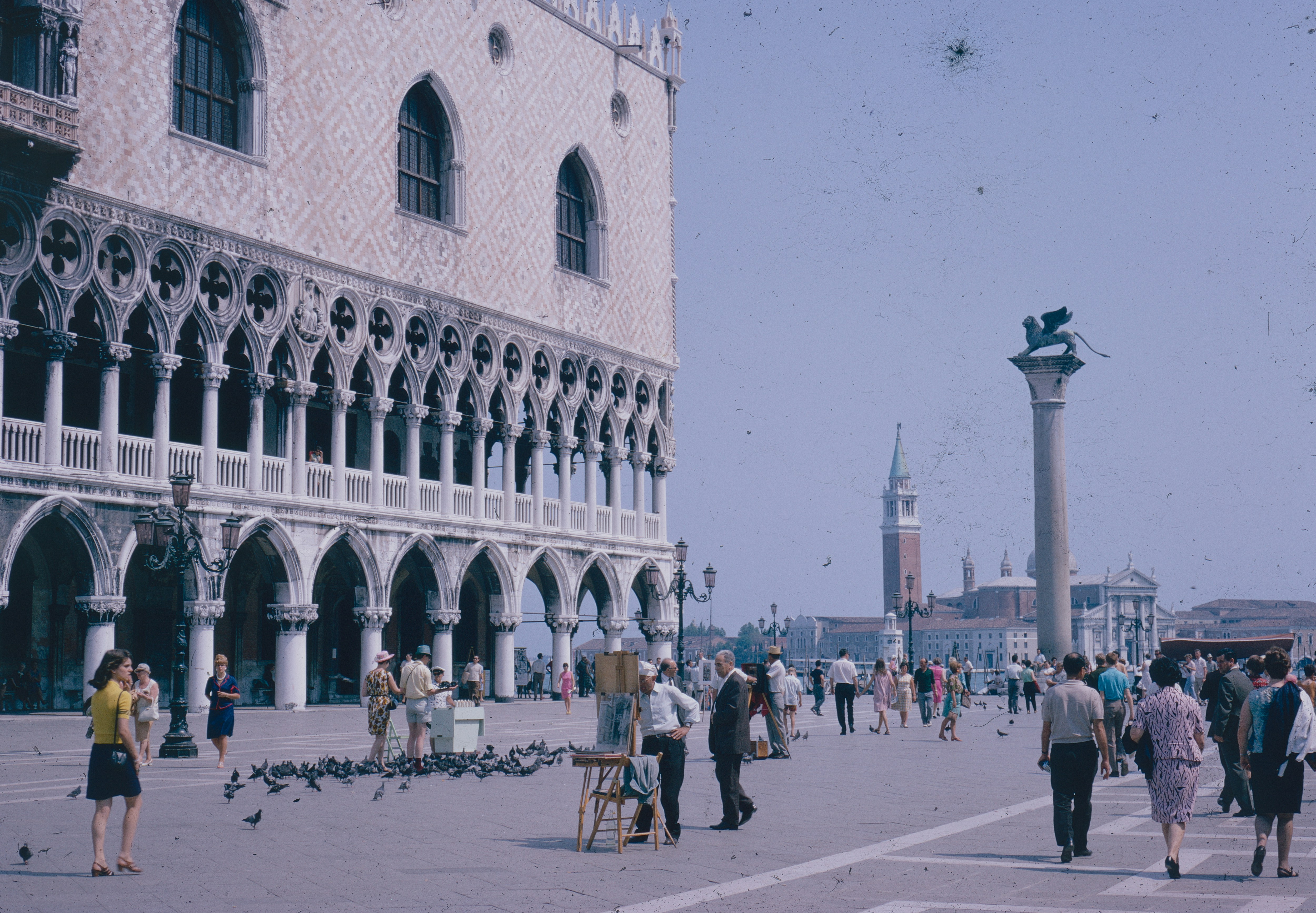 a group of people walking in a plaza with a tall building in the background