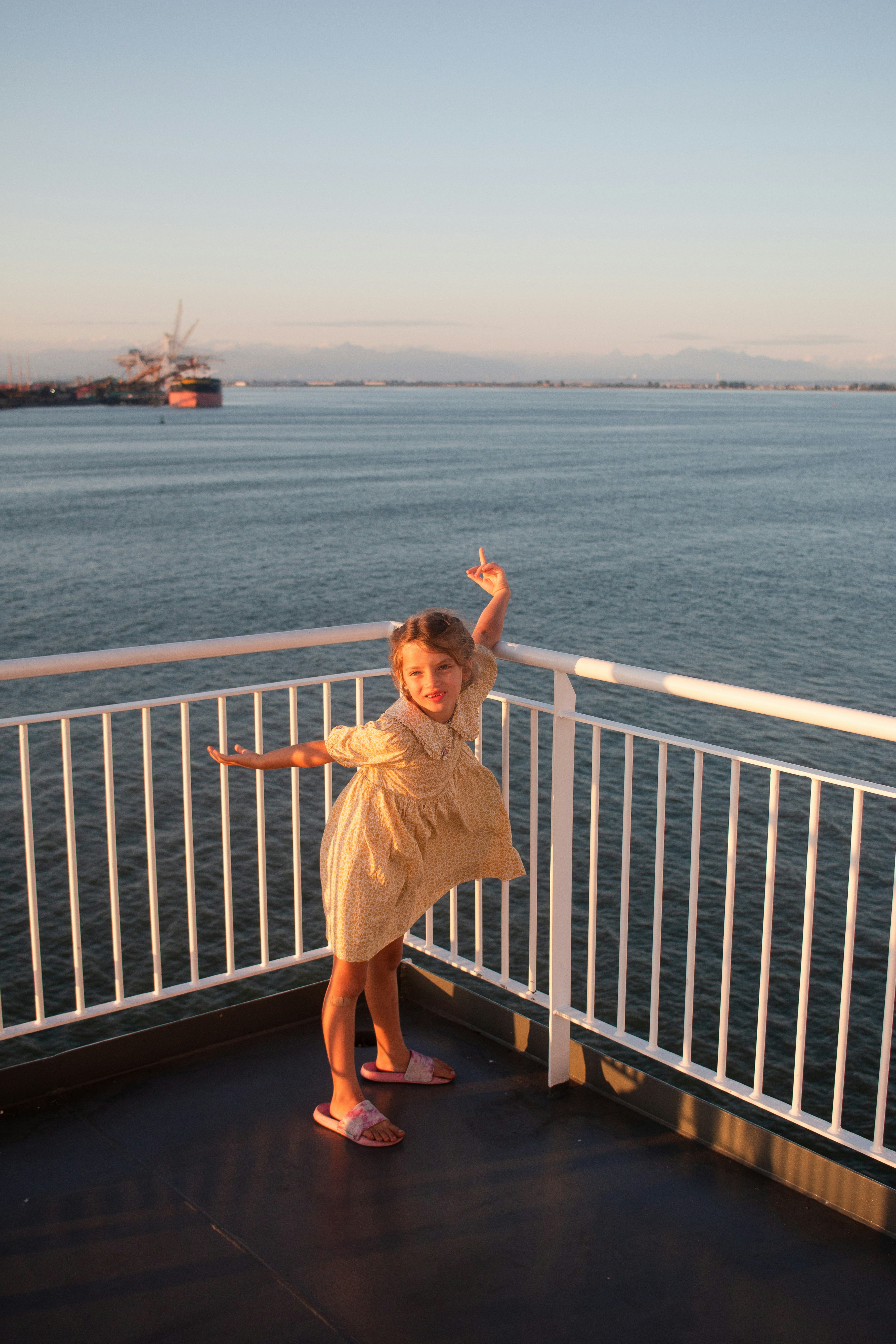 A girl standing on a railing overlooking a body of water photo – Free ...