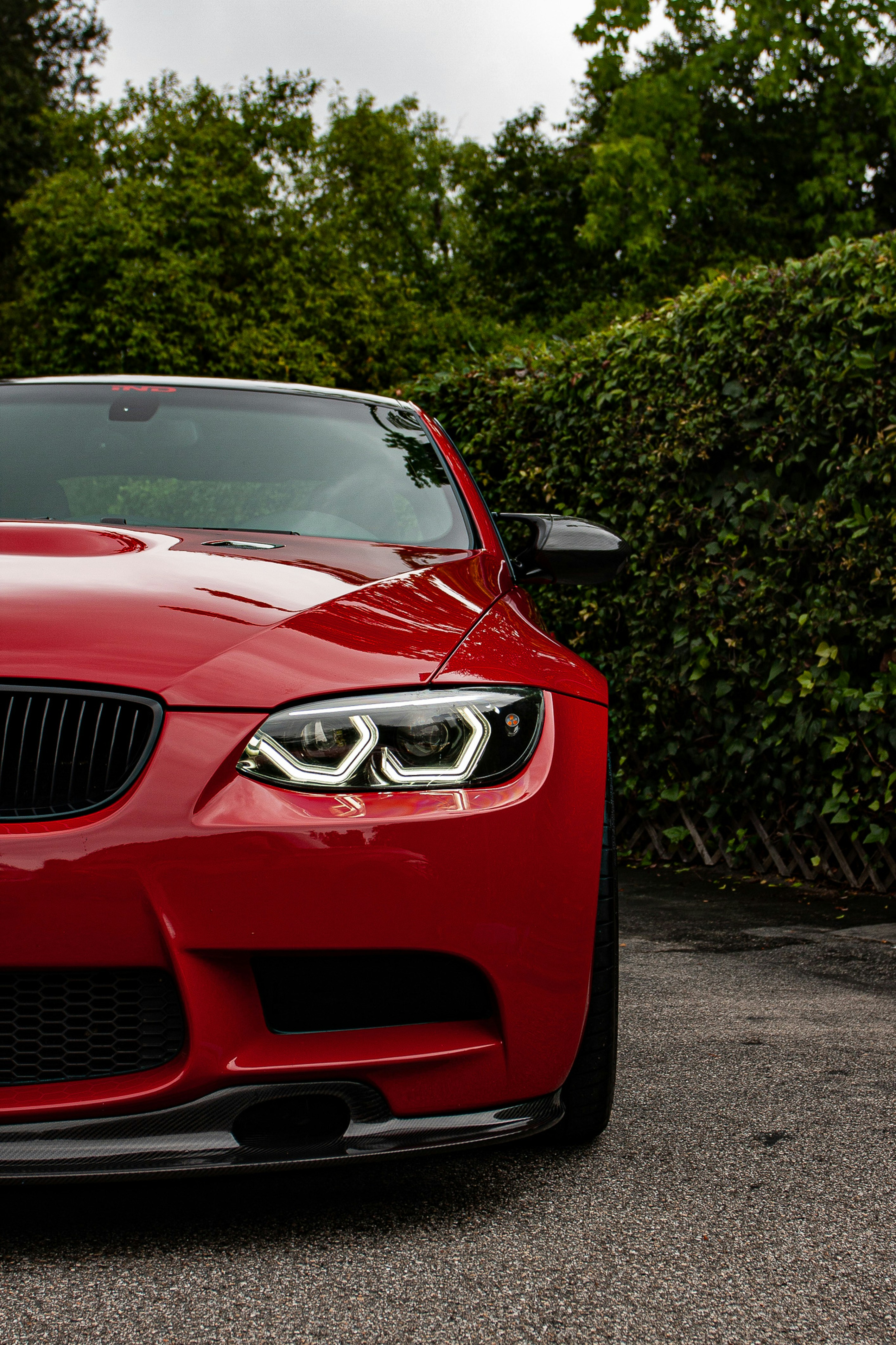 A red car parked in front of a hedge photo – Free Image on Unsplash
