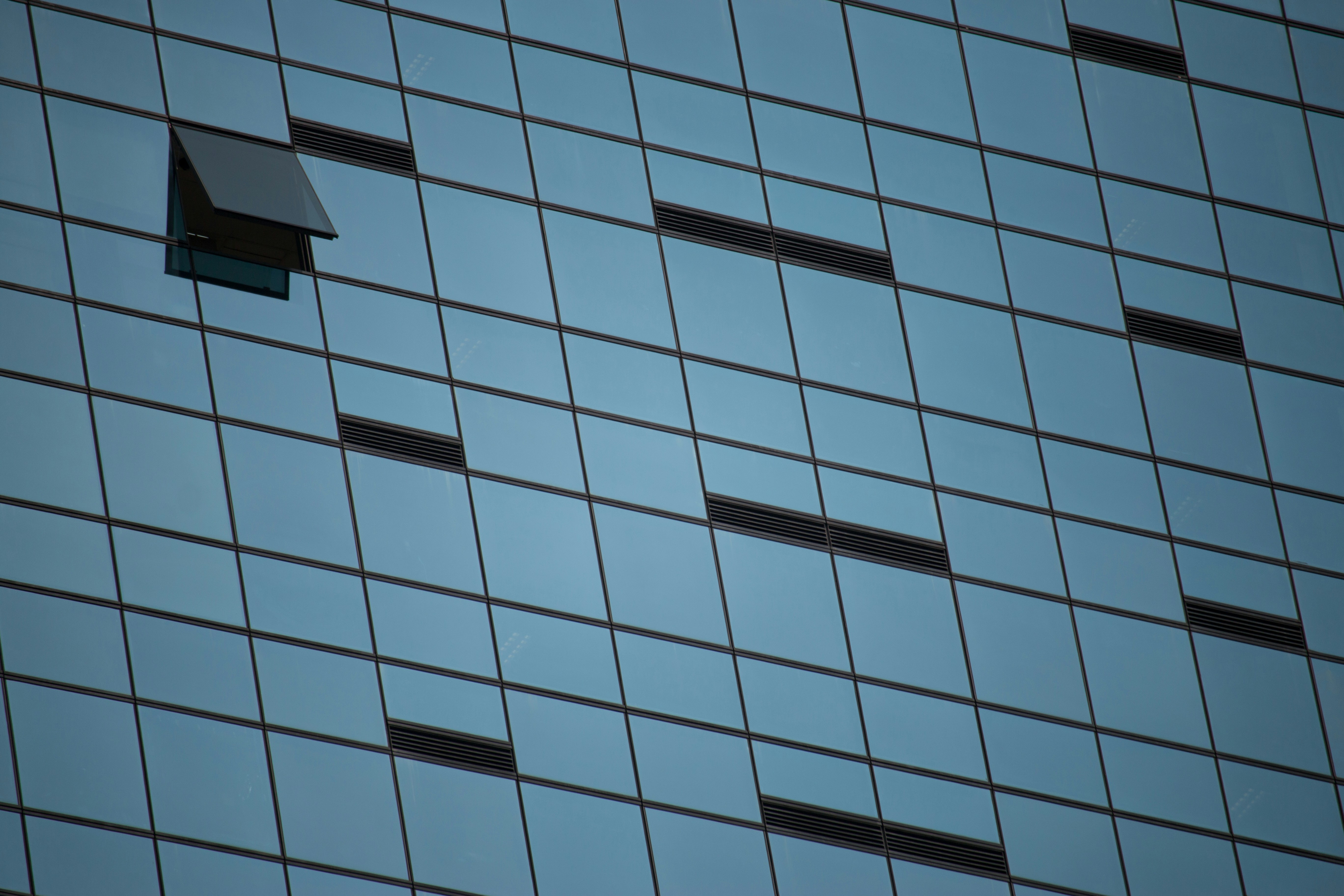 Abstract view of a glass building facade featuring a lone window and horizontal slits, showcasing contemporary architectural design.