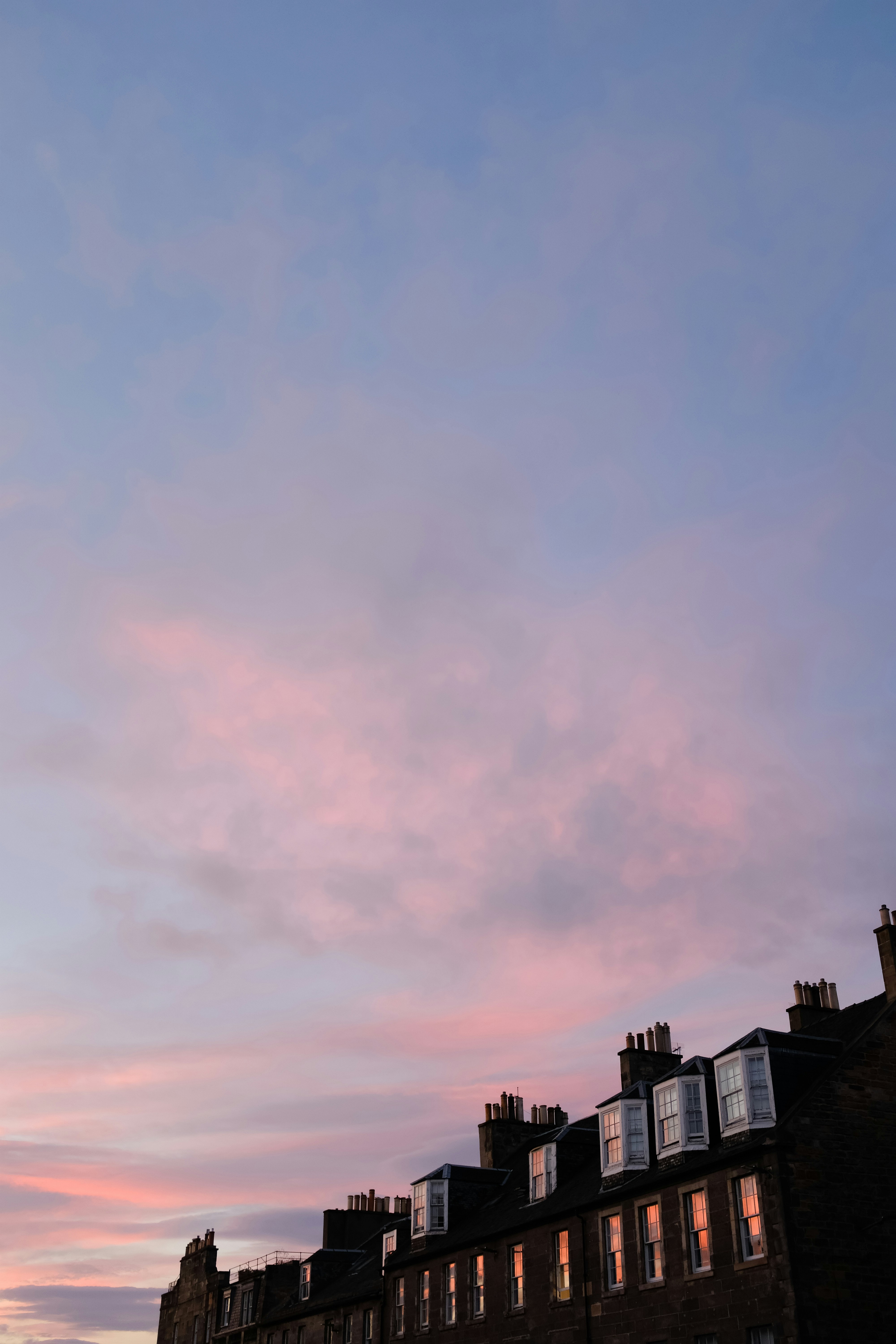 Dusk Over Brick Row Houses: Pink Clouds Weave Above Chimney Tops