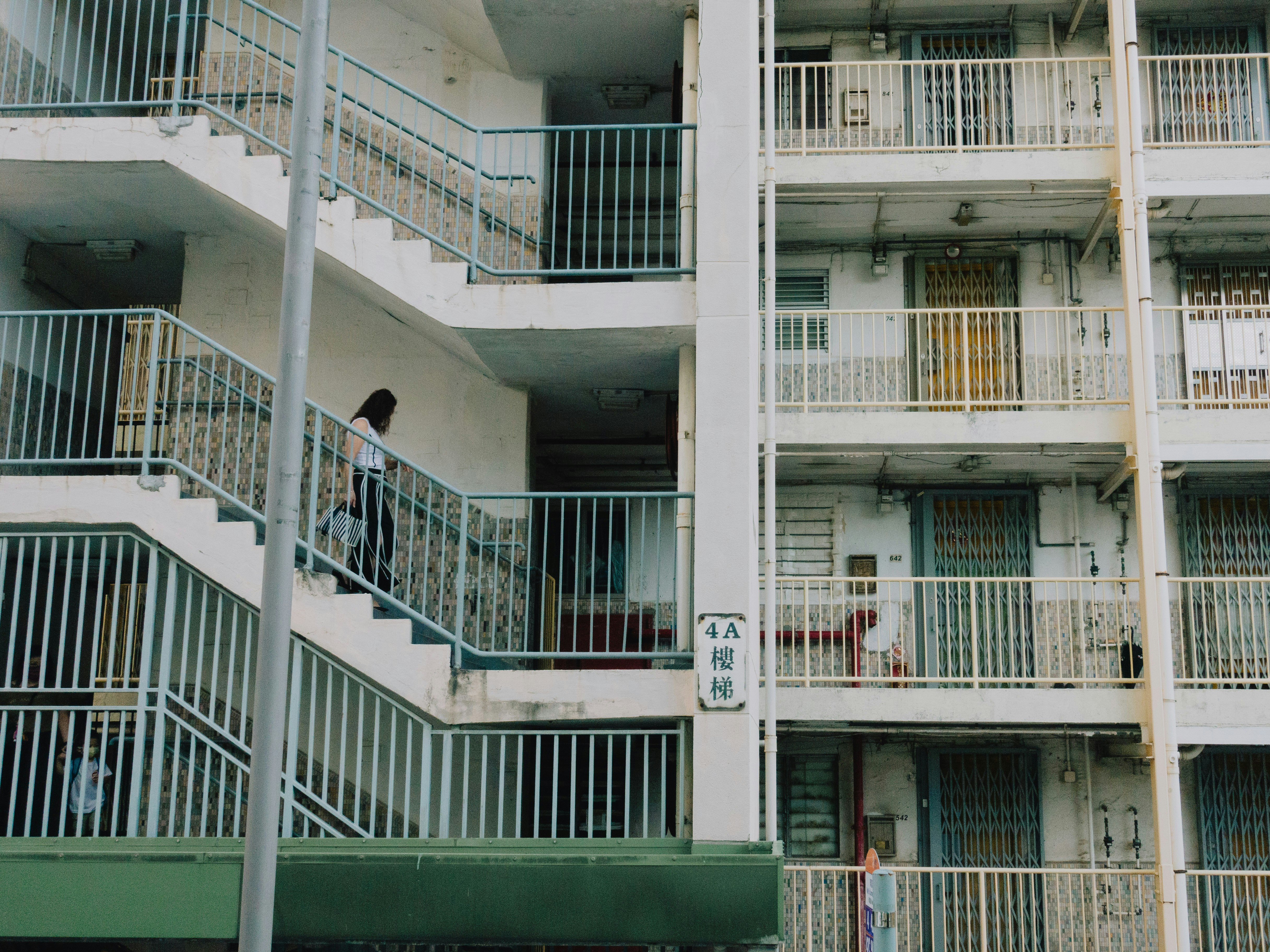 Stairwell Grid: A lone figure threads the balcony maze