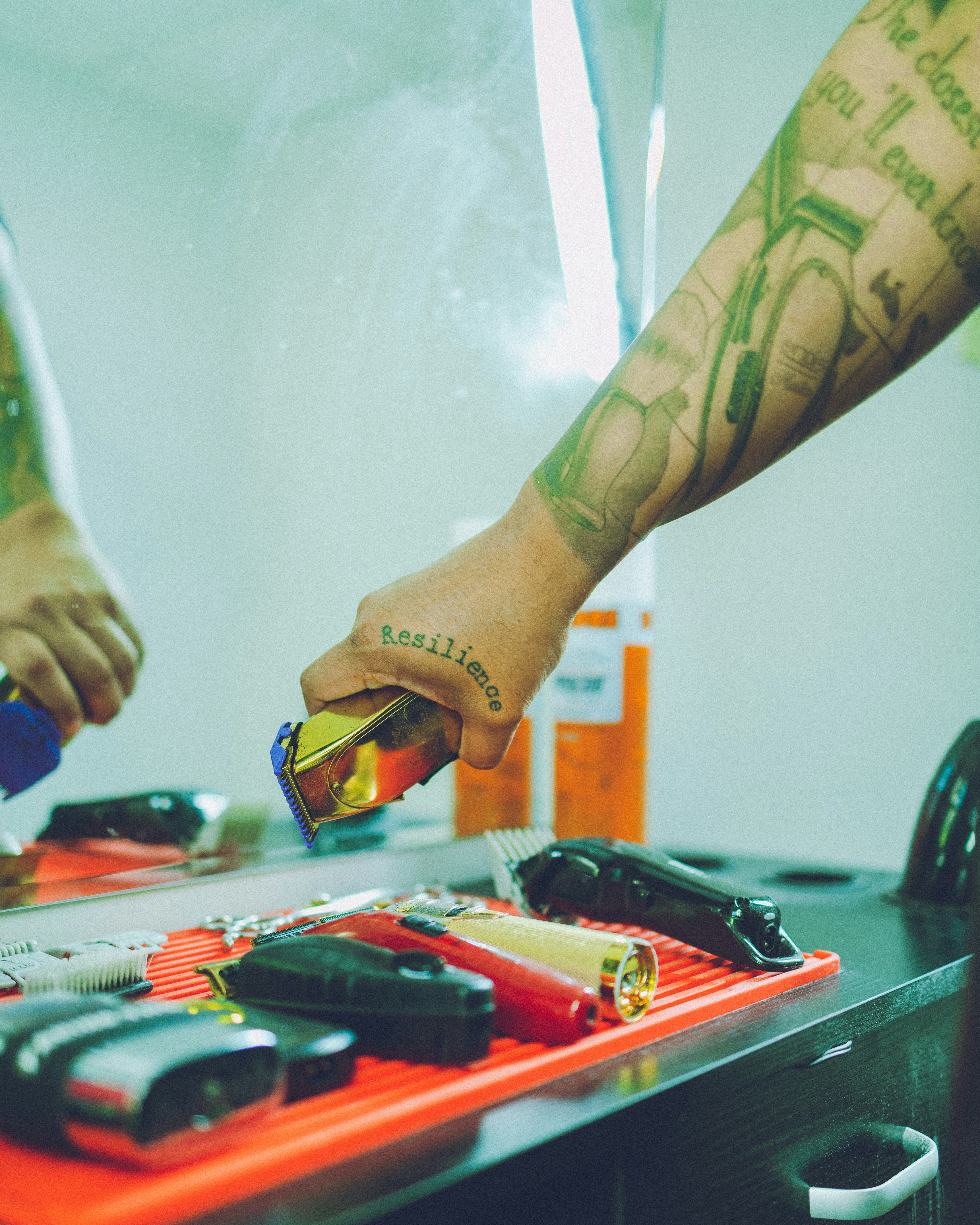 Tattooed Hand Grasping a Cutter Over a Workbench of Tools