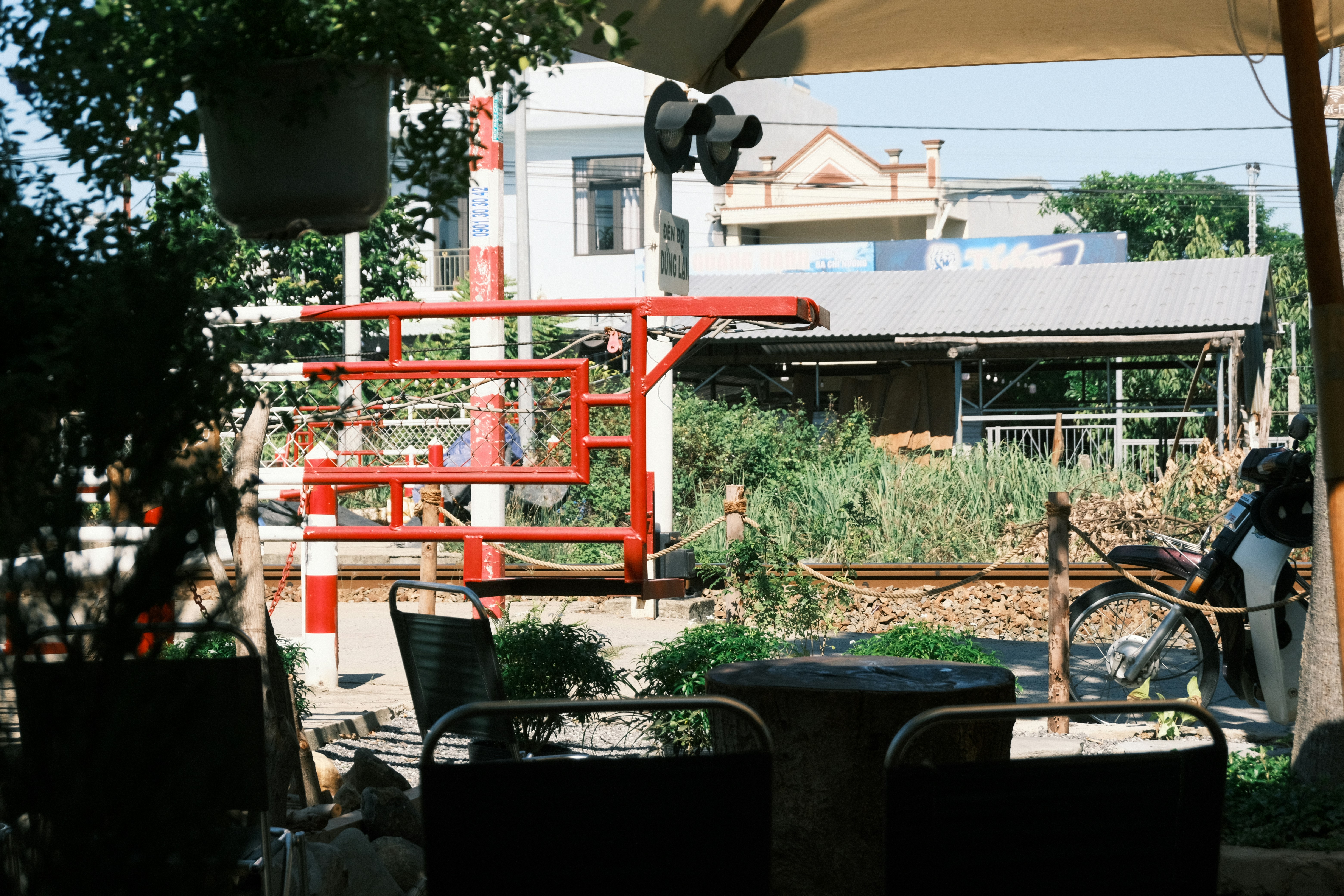 Red Railings and Quiet Garden Café Under a Sunlit Awning