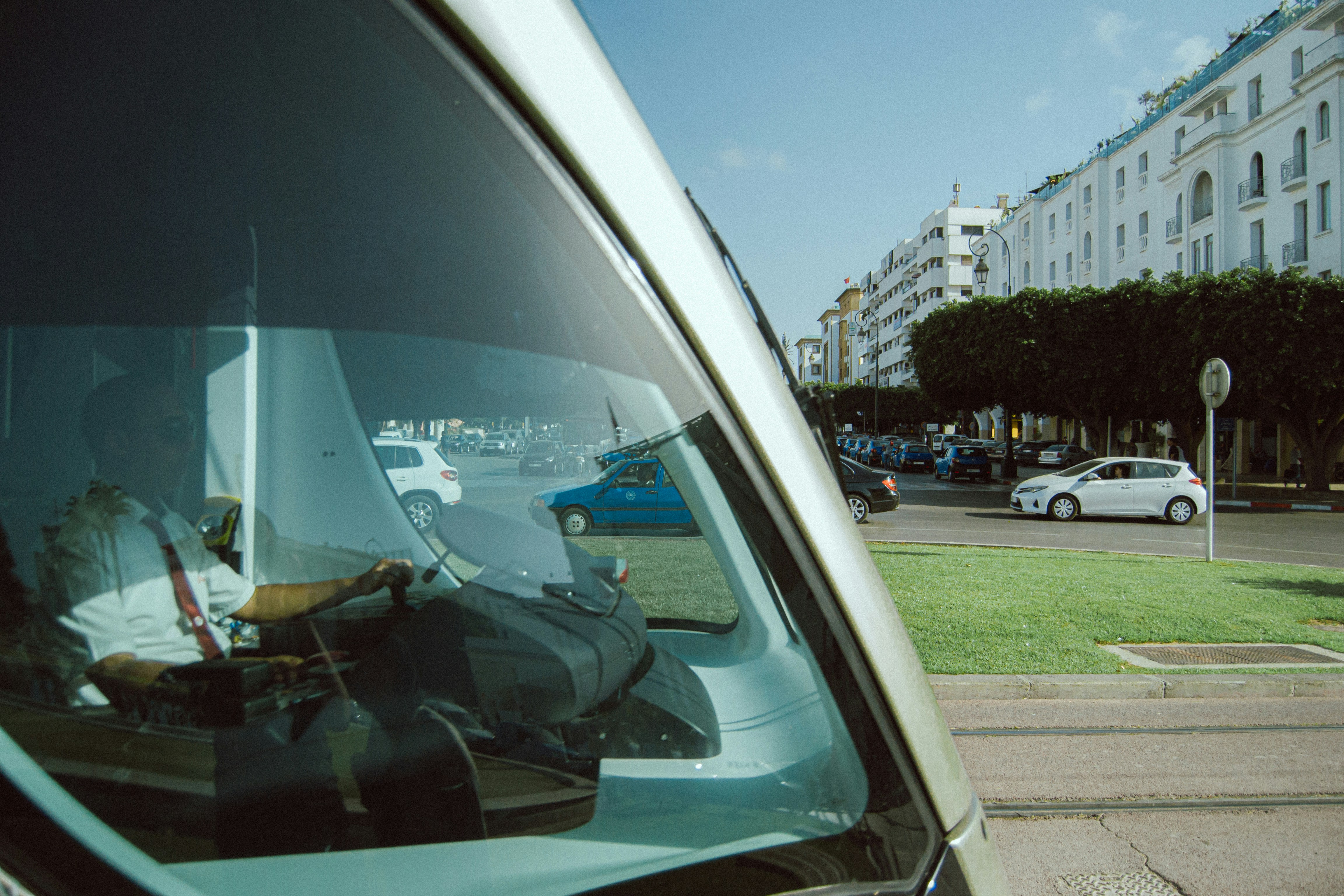 Windshield Vista: A Sunlit Avenue Framed by a Vehicle's Glass
