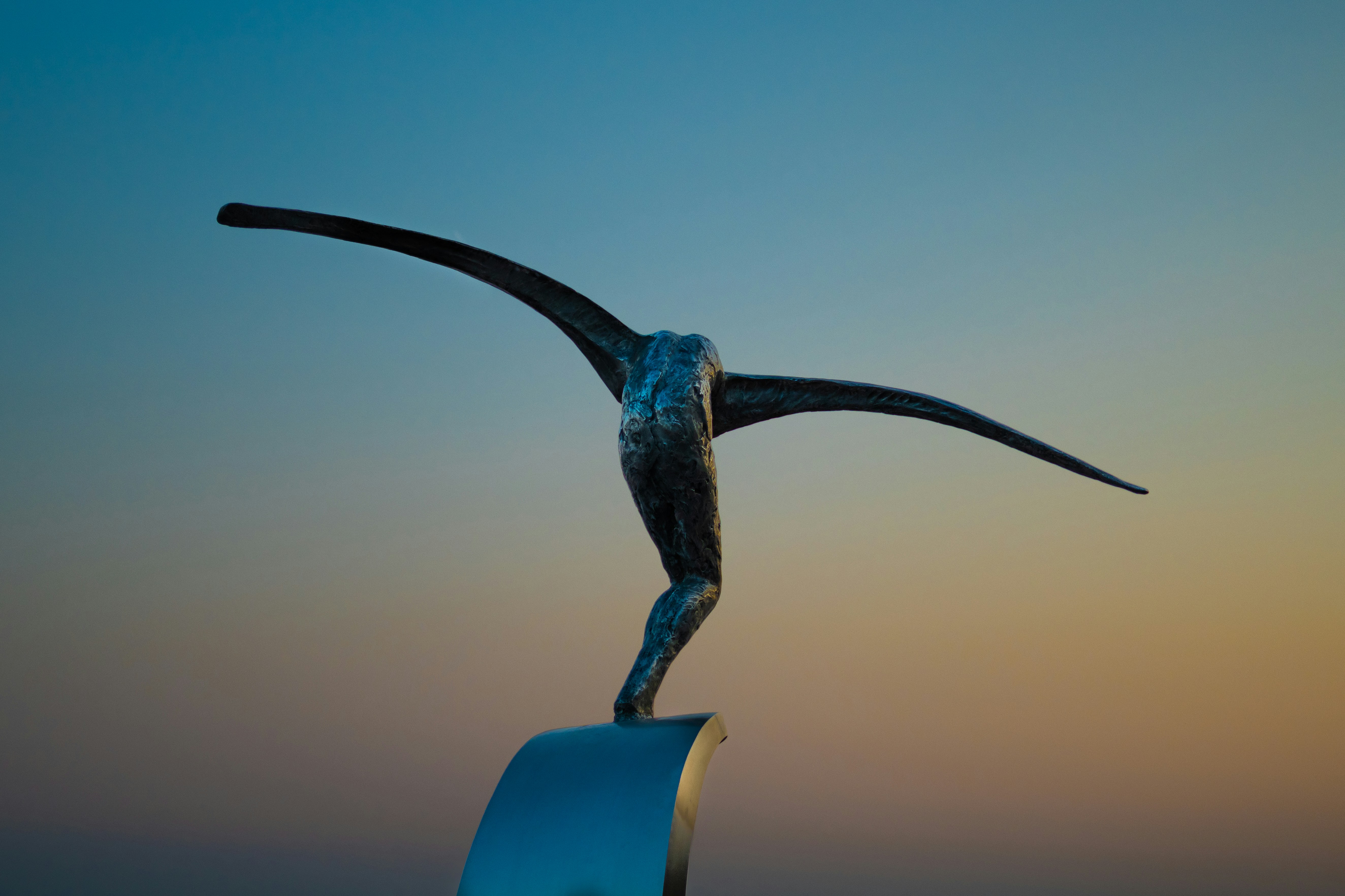 Dusk Gull on a Curved Crest: A Metal Statue Reaches for Light