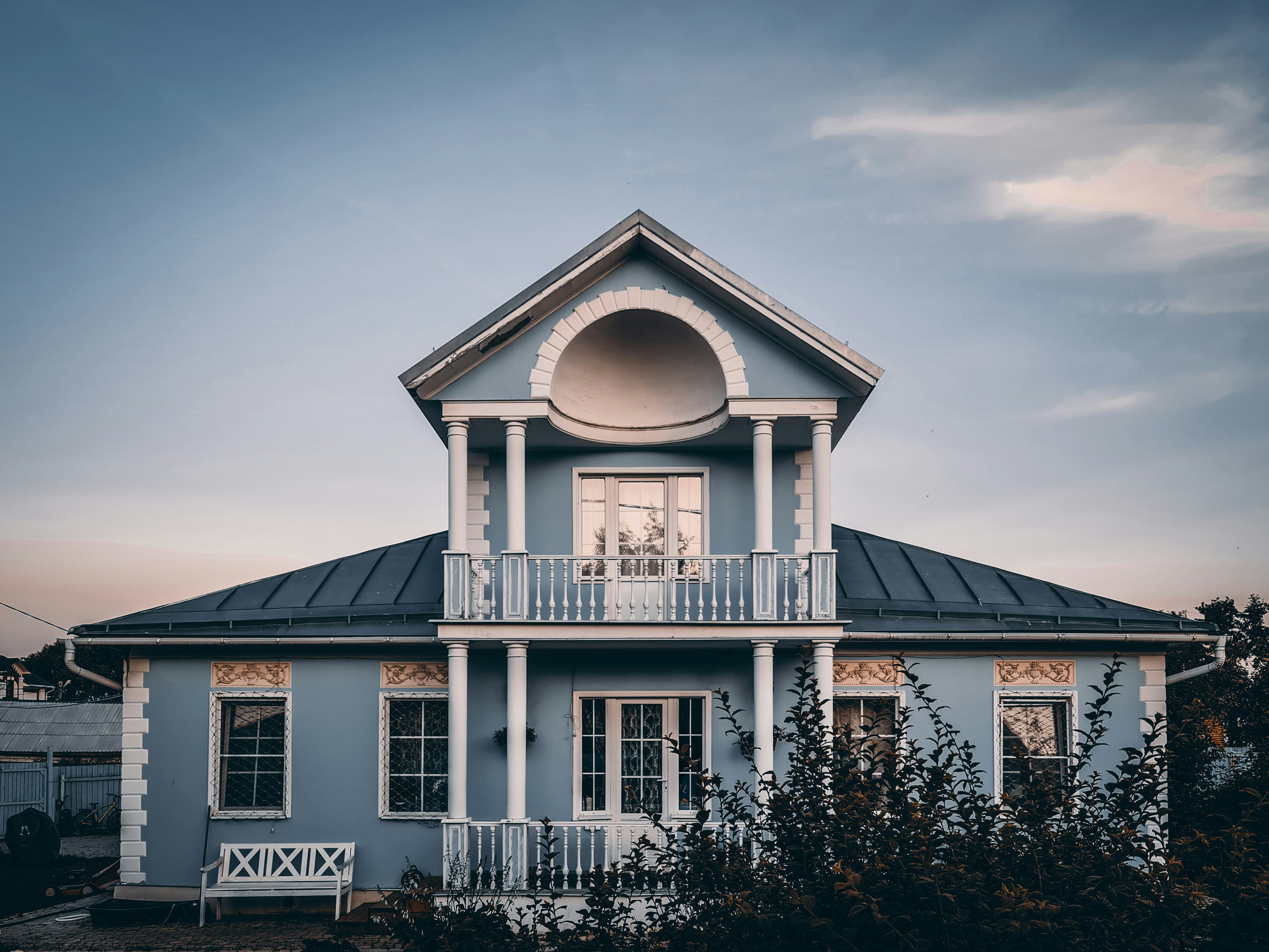 Charming blue house with white accents under a soft evening sky.