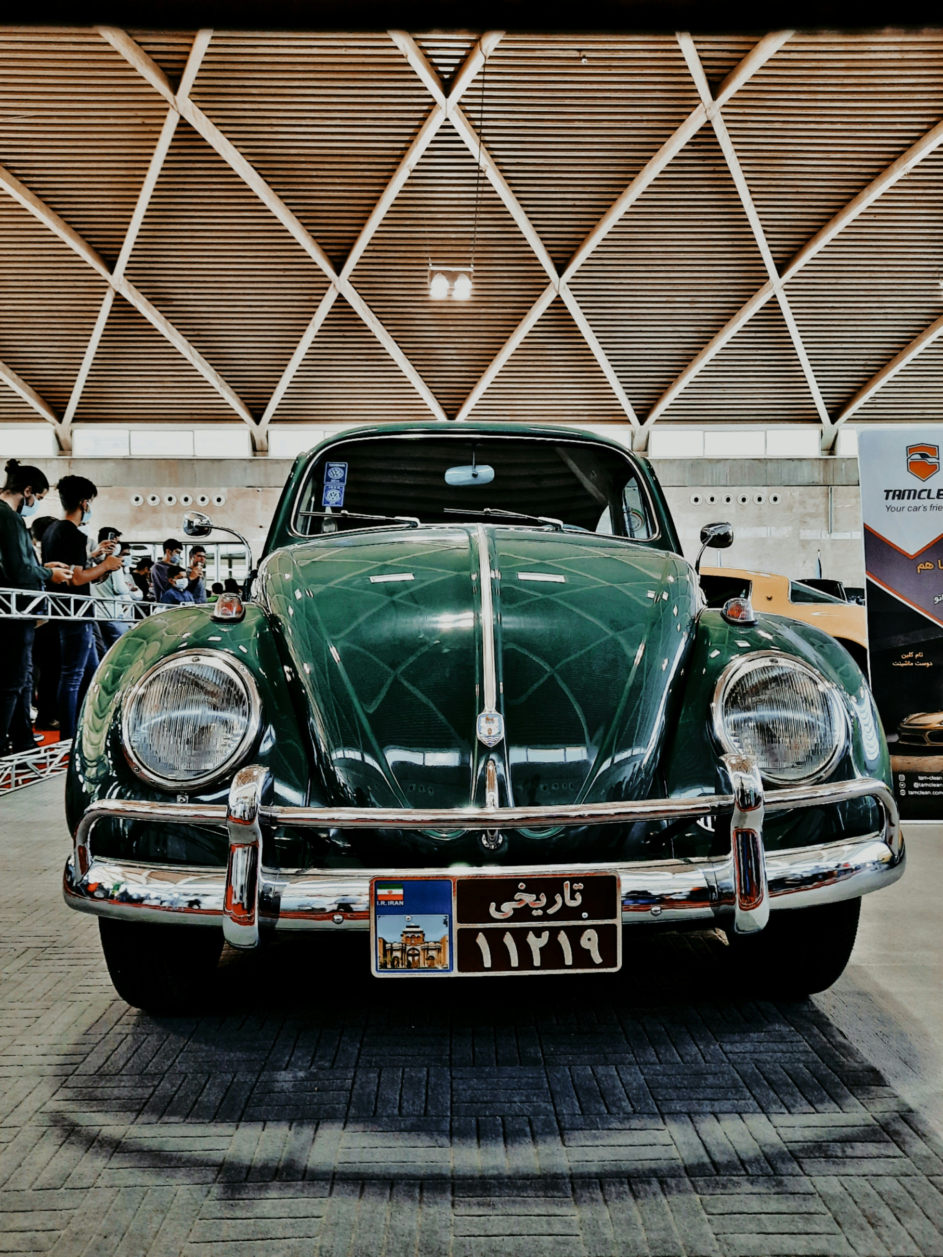 Emerald Classic: Front View of a Vintage Green VW in an Indoor Exhibition