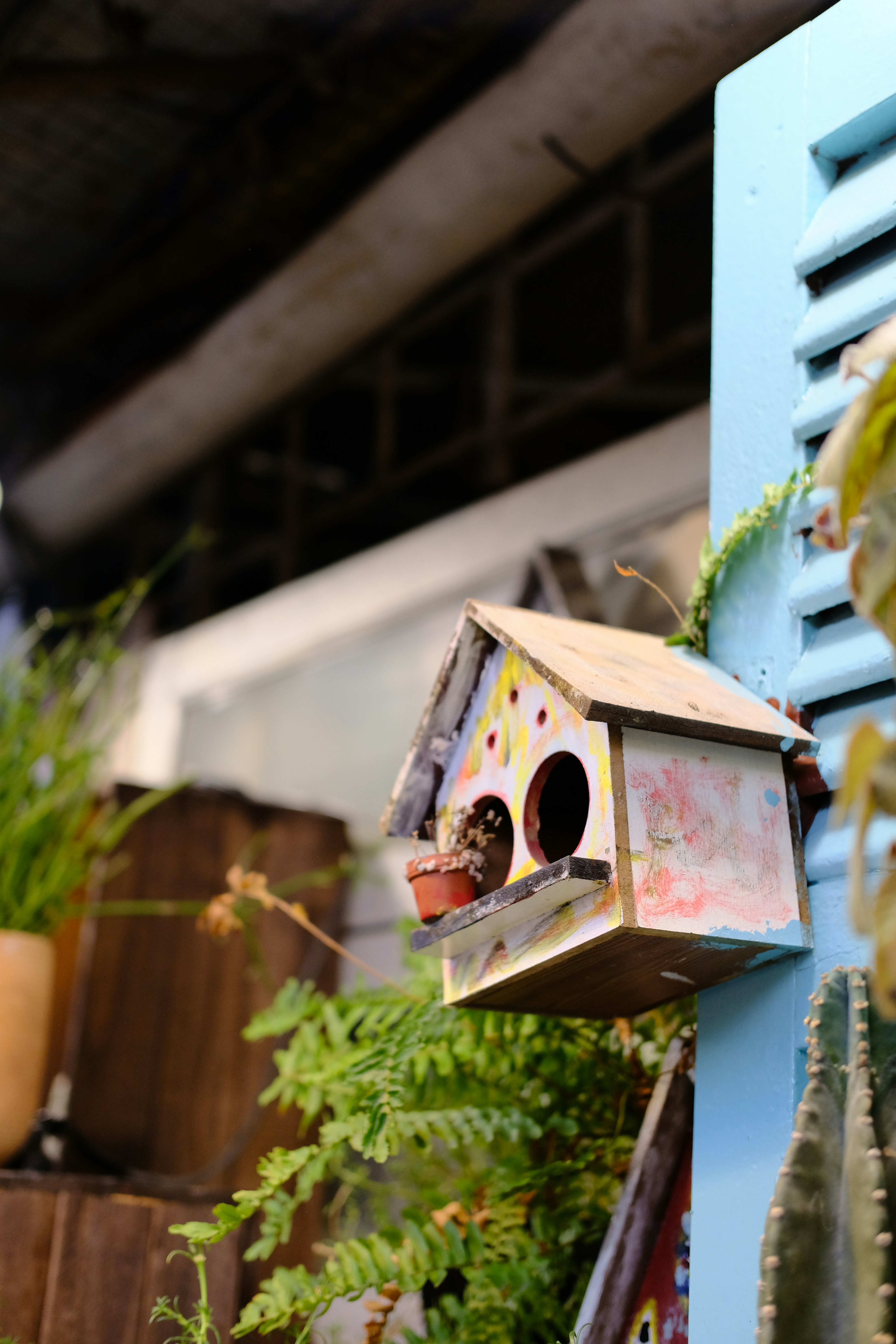 Whimsical Birdhouse Beside a Weathered Blue Window