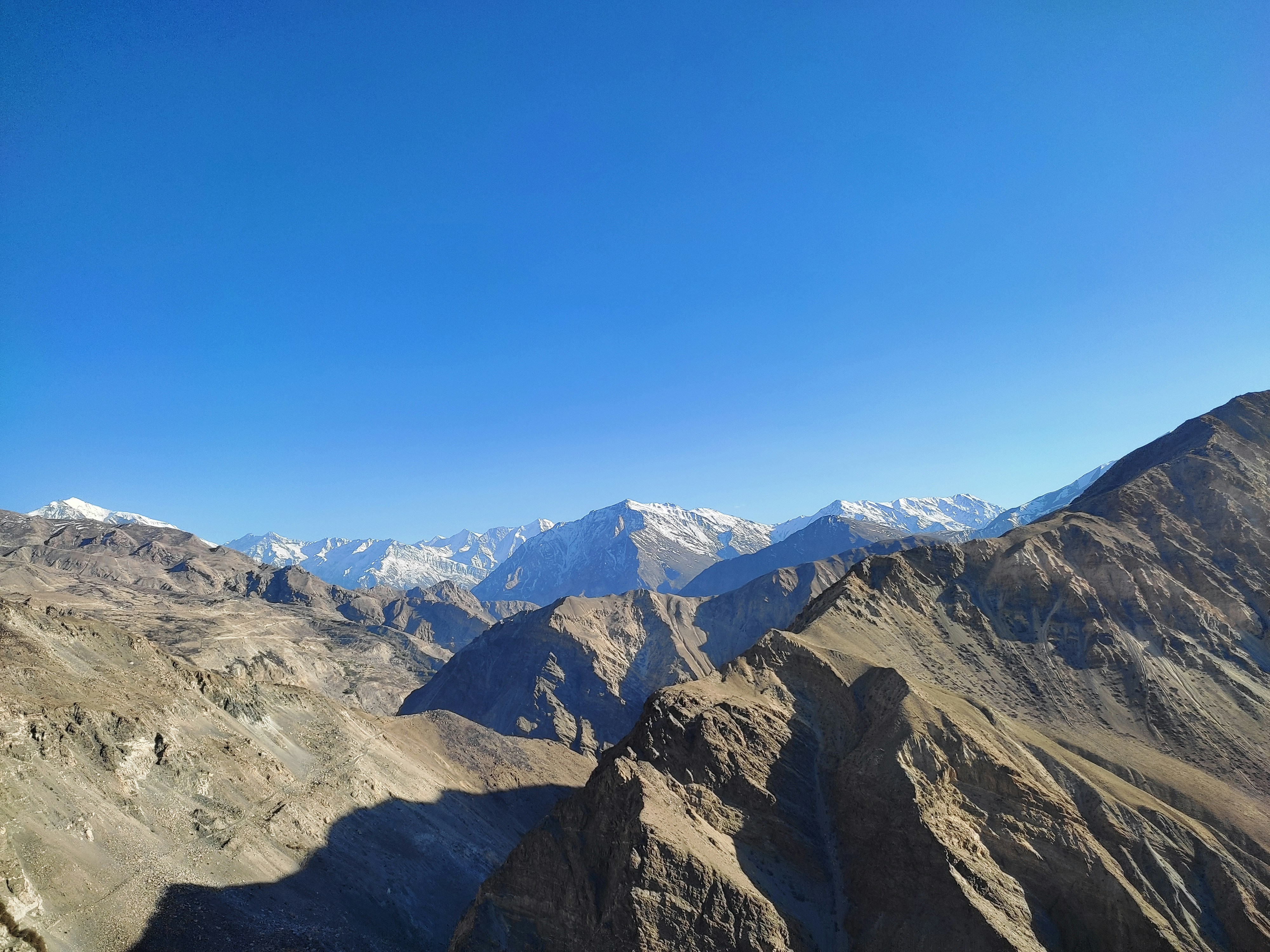 Snow-kissed Peaks Framing a Desert Ridge Under a Crisp Blue Sky