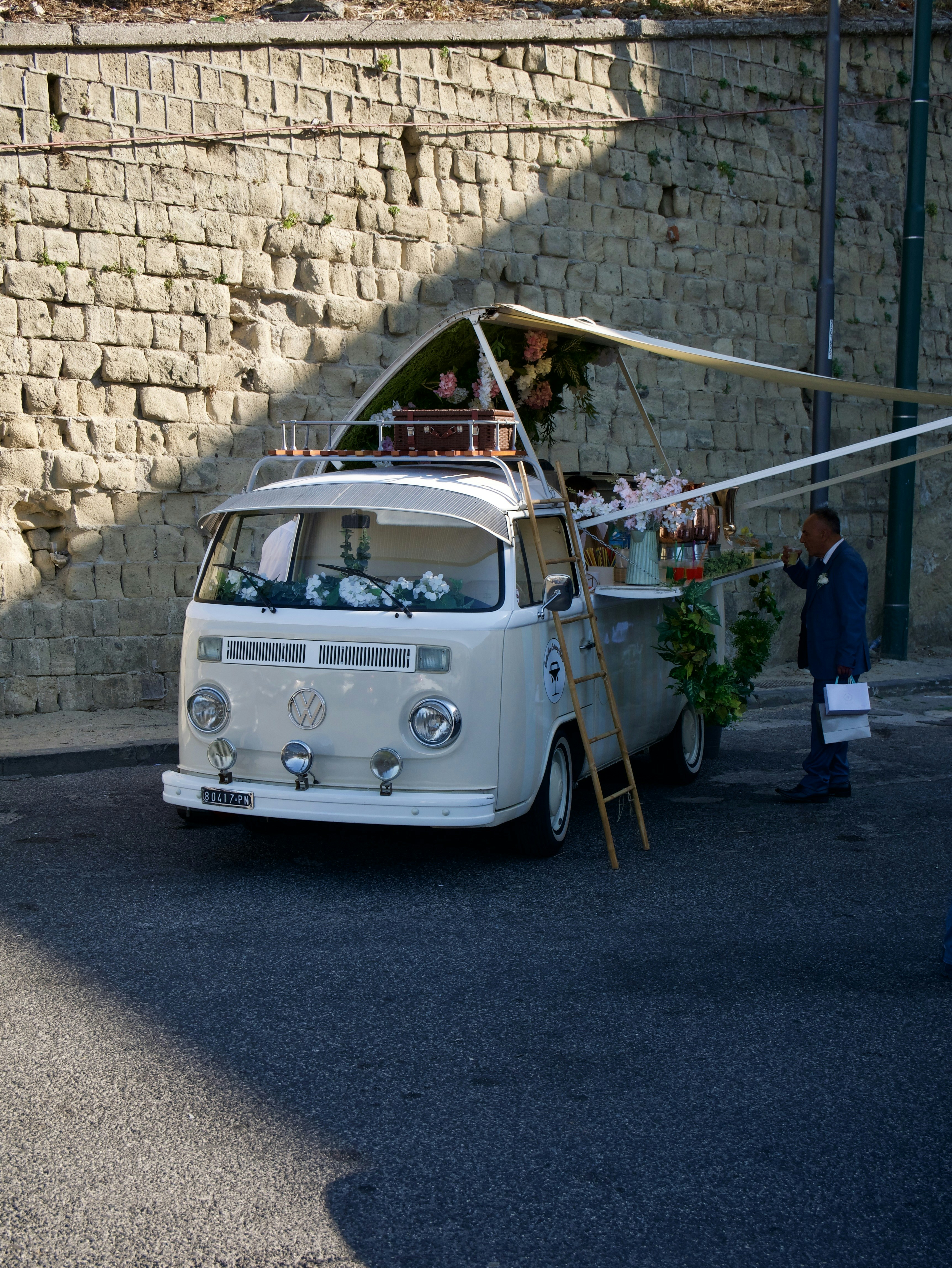 Bloom-Draped Vintage VW Wedding Van by a Weathered Stone Wall