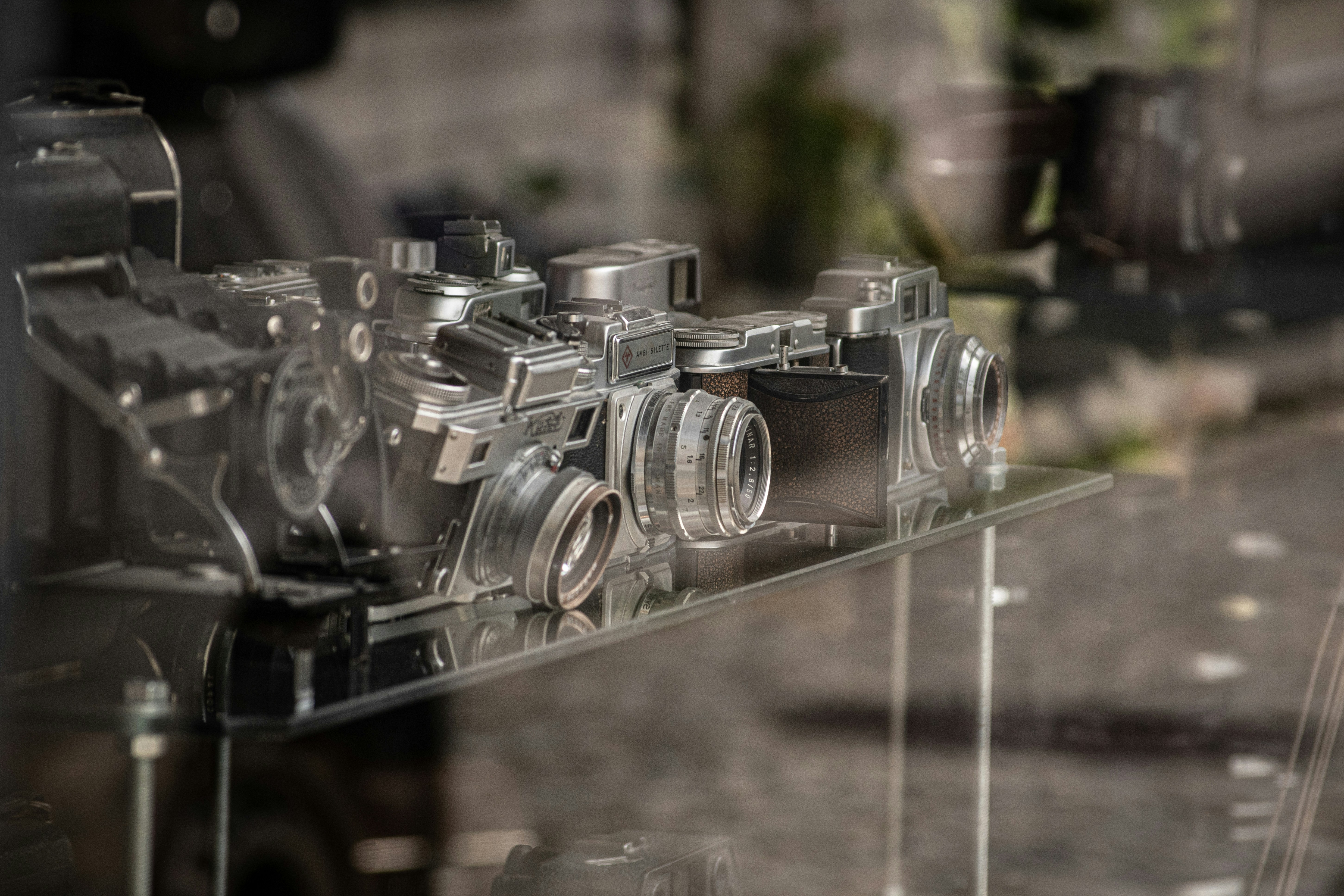 Reflections of Precision: A Row of Vintage Rangefinder Cameras on Glass