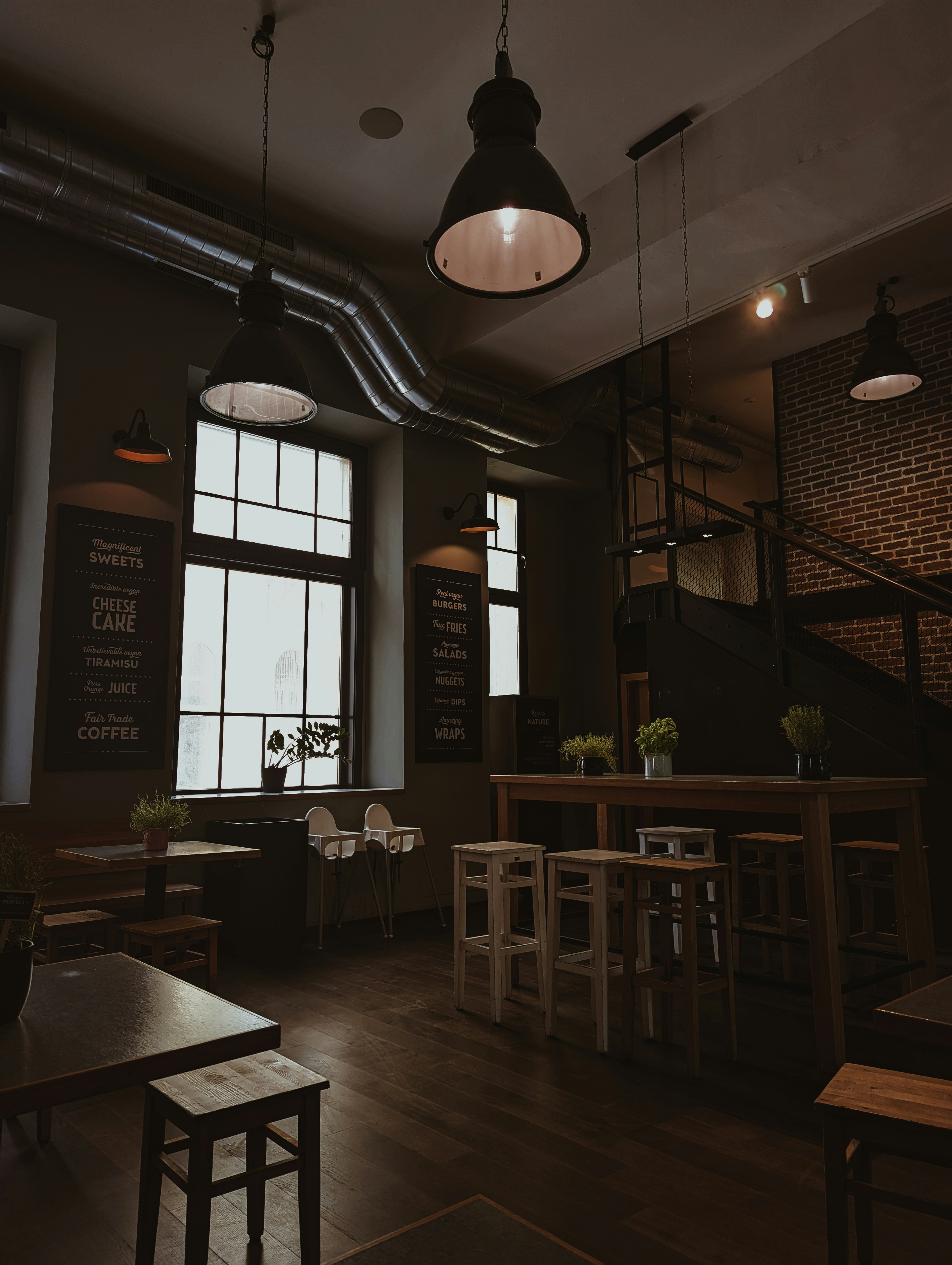 Inviting café interior featuring wooden furniture, warm lighting, and decorative plants. A perfect spot for relaxation and socializing.