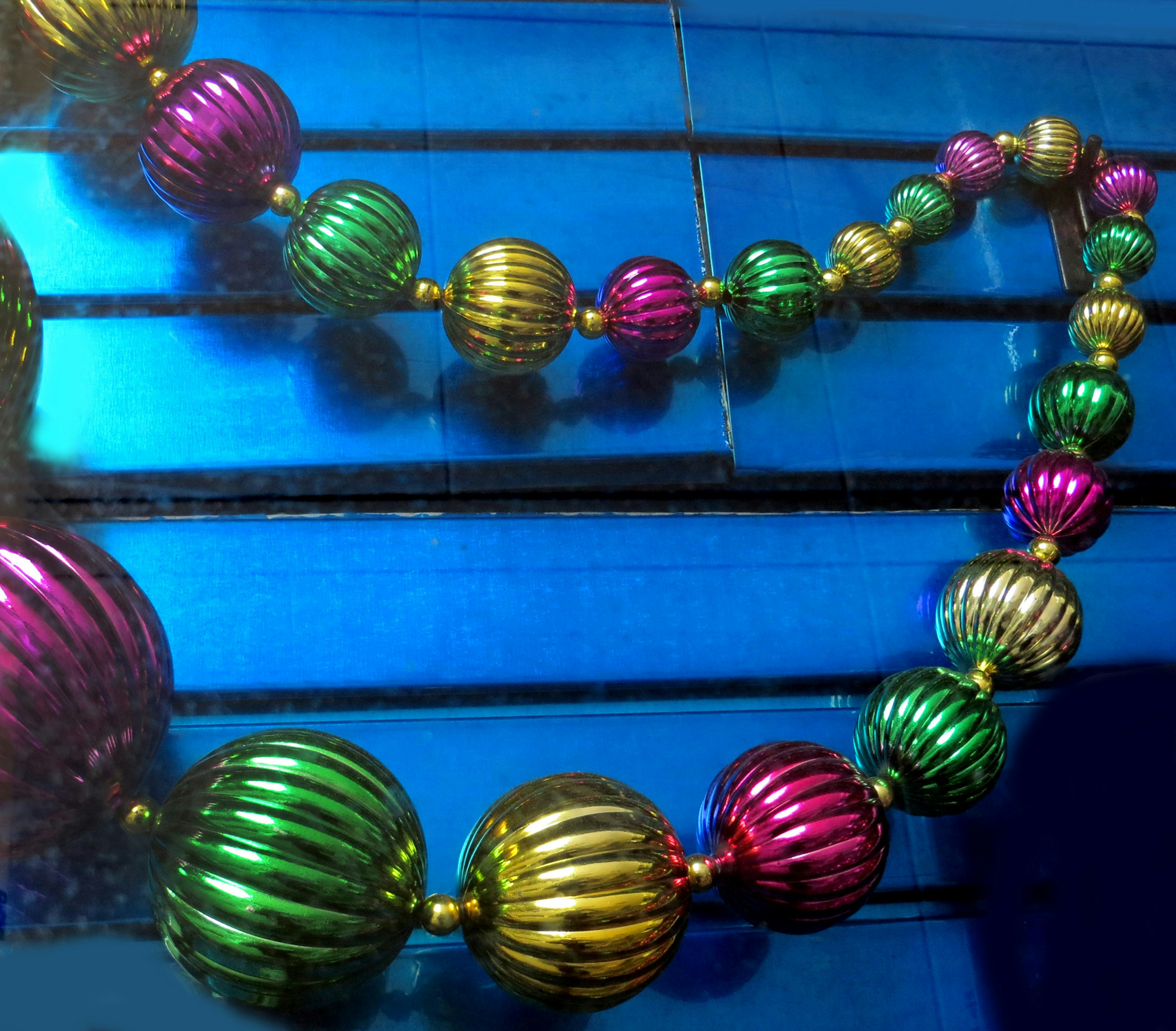 Colorful metallic ornaments arranged in a flowing pattern against a blue backdrop.