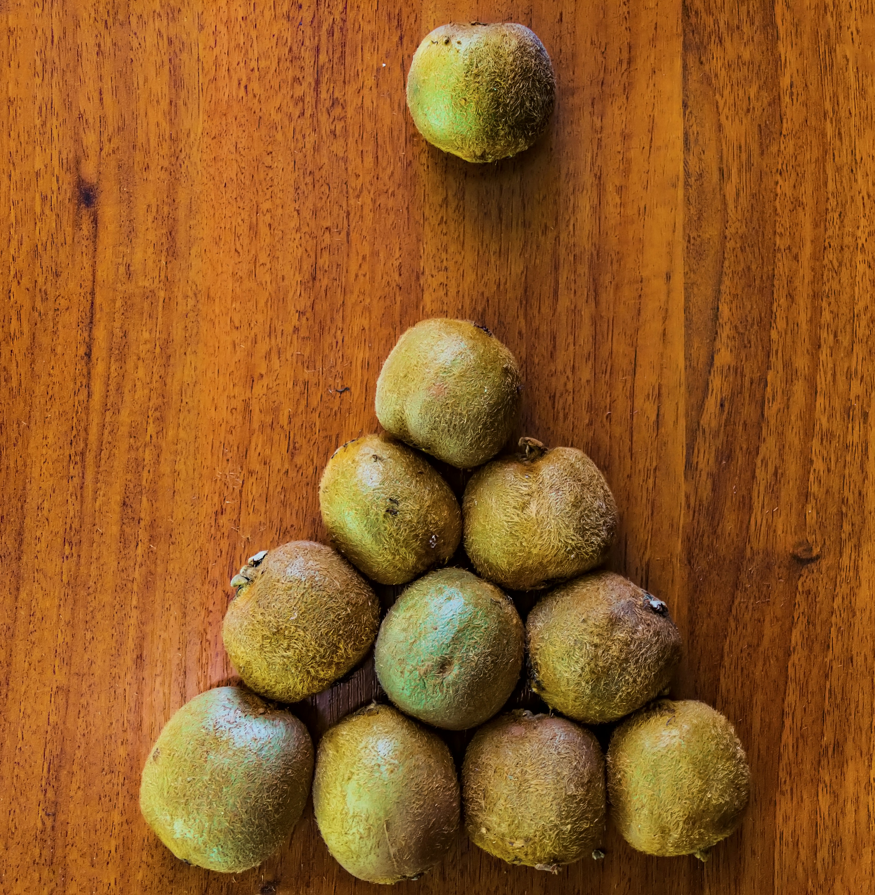 Some ripe fresh kiwi on the wooden table as though balls on the pool